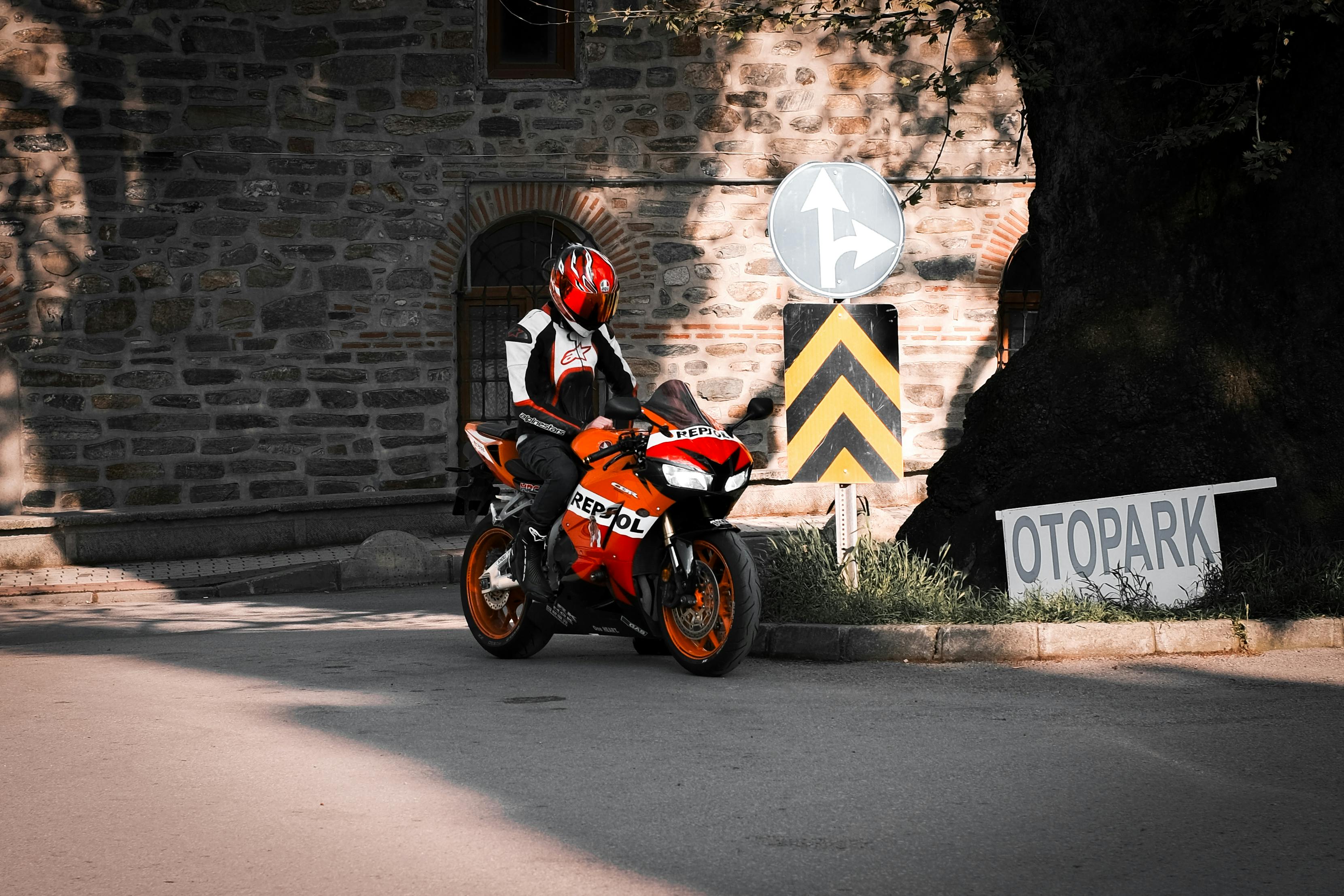 Motorcyclist Poses Near Parking Sign Outdoors · Free Stock Photo