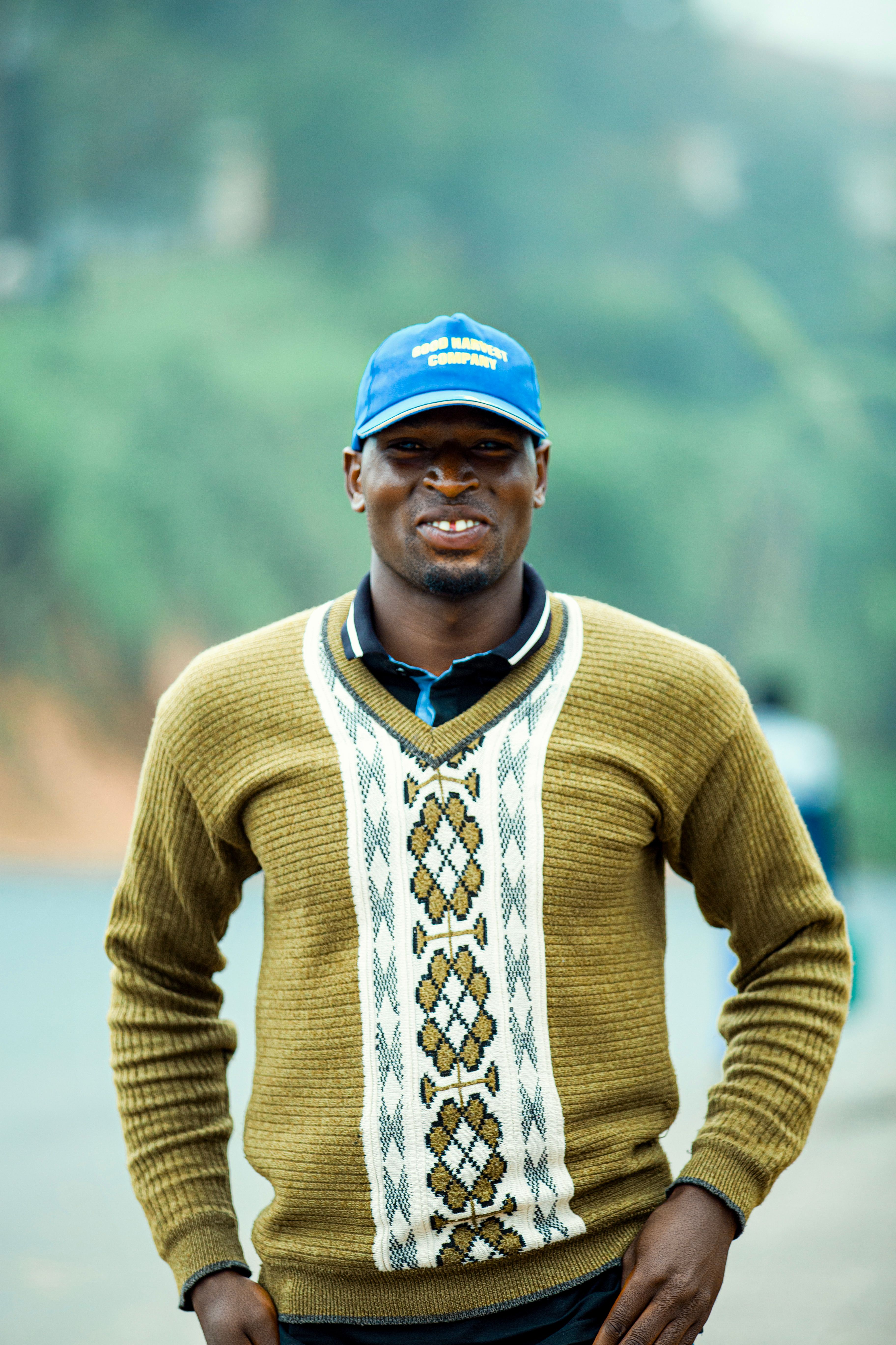 Young Man in Brown Sweater Smiling Outdoors · Free Stock Photo