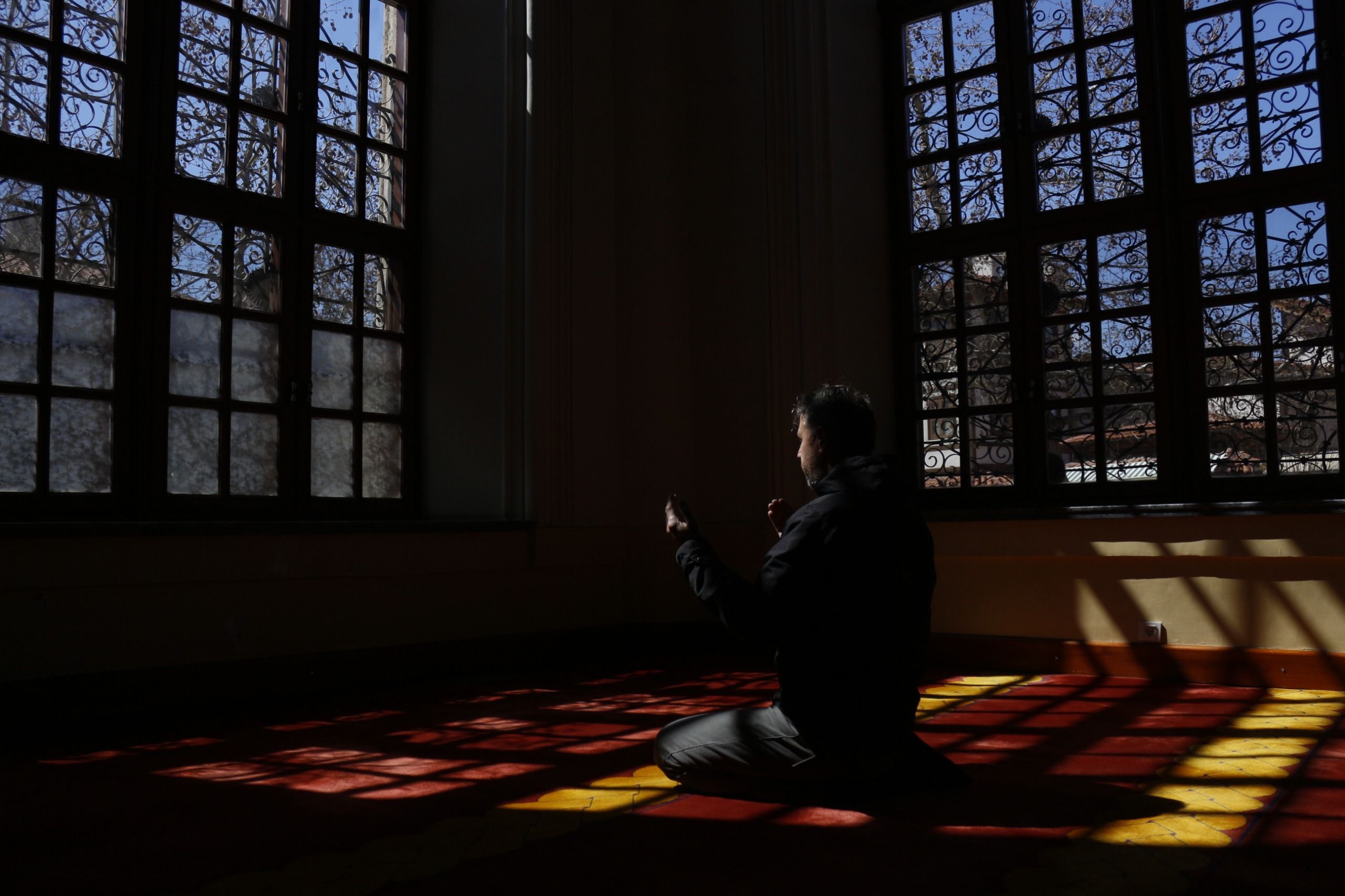 Man Praying in Sunlit Room with Stained Glass · Free Stock Photo