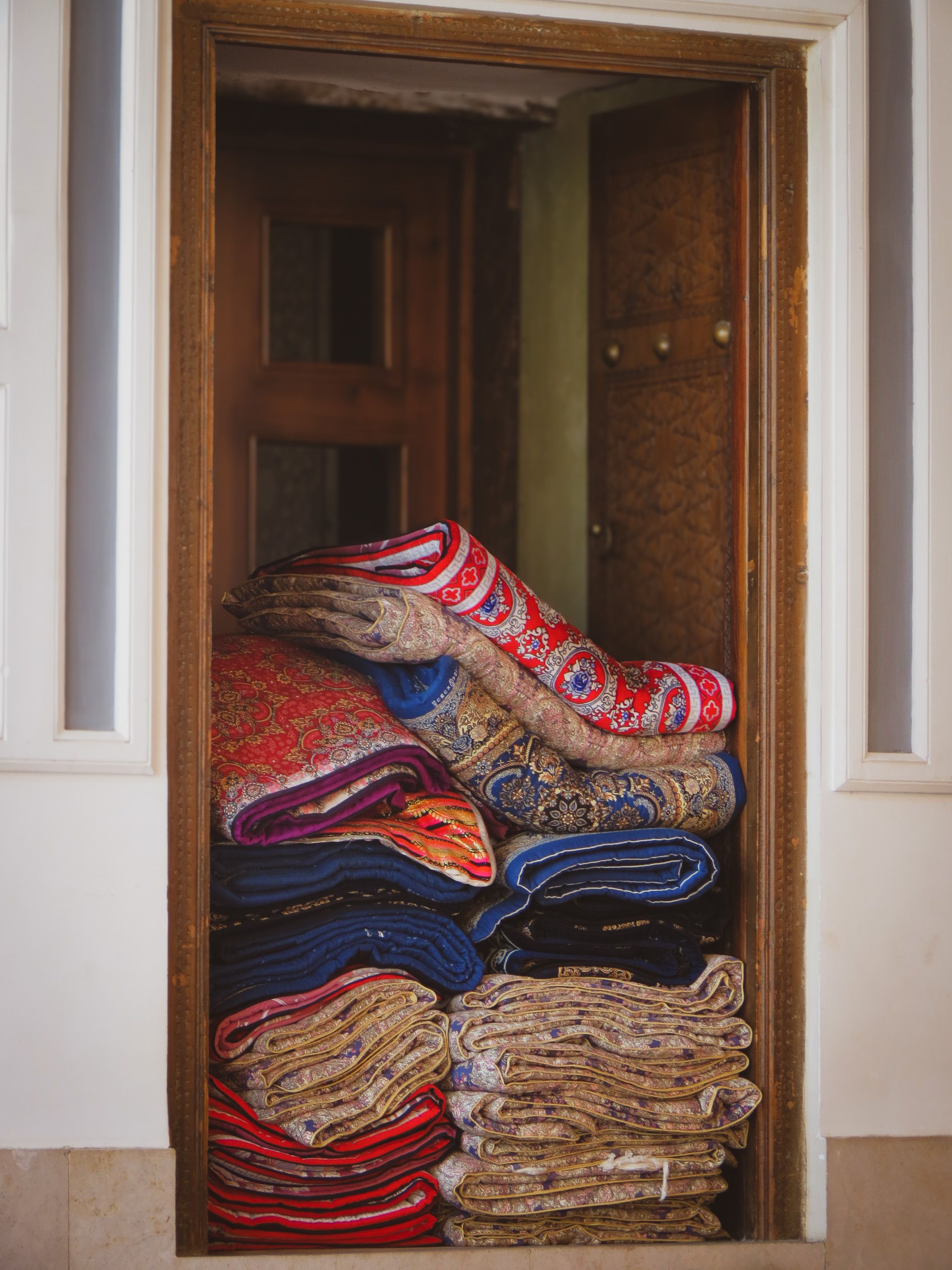 Vibrant Stacked Carpets in Wooden Doorway · Free Stock Photo