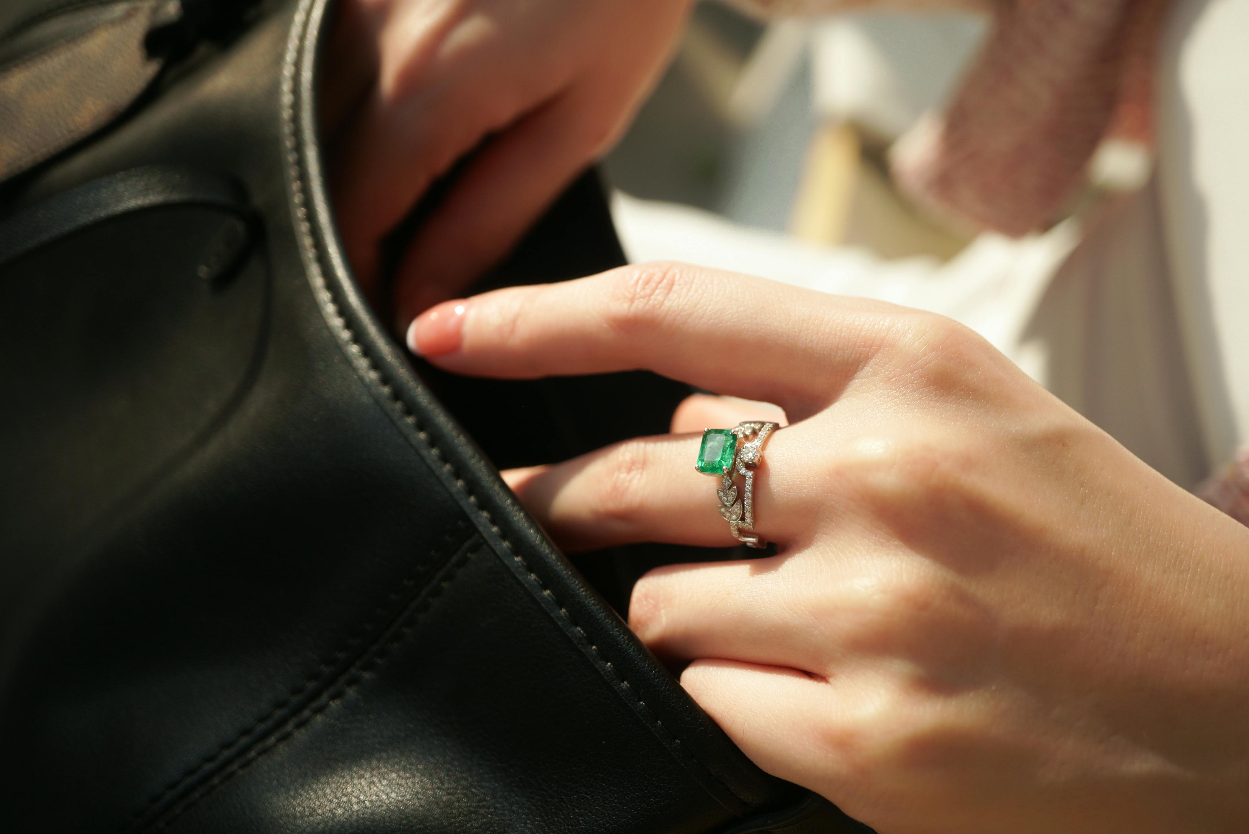 Elegant Hand with Emerald Ring Accessorizing a Bag · Free Stock Photo