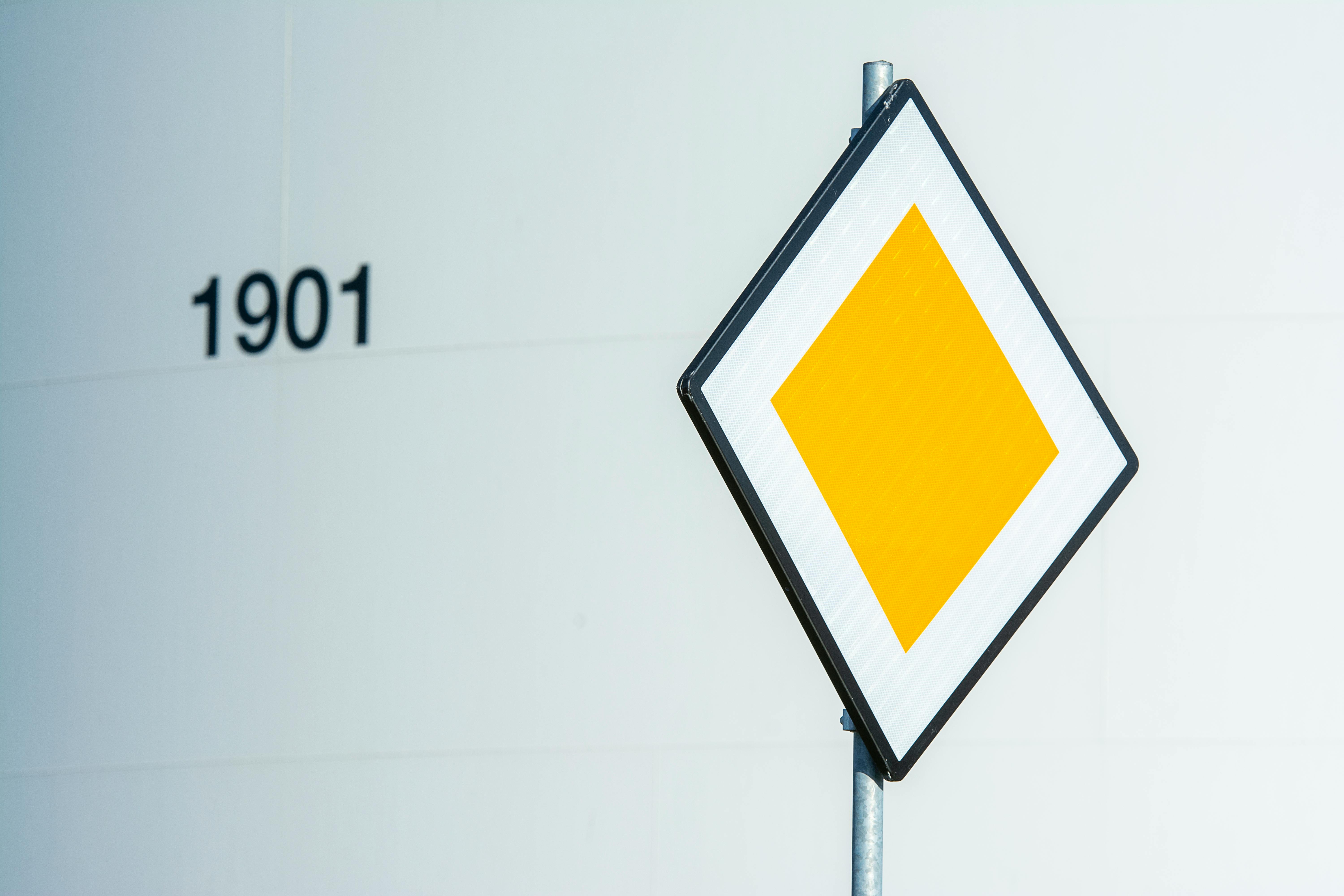 Yellow Diamond Traffic Sign on Industrial Background · Free Stock Photo