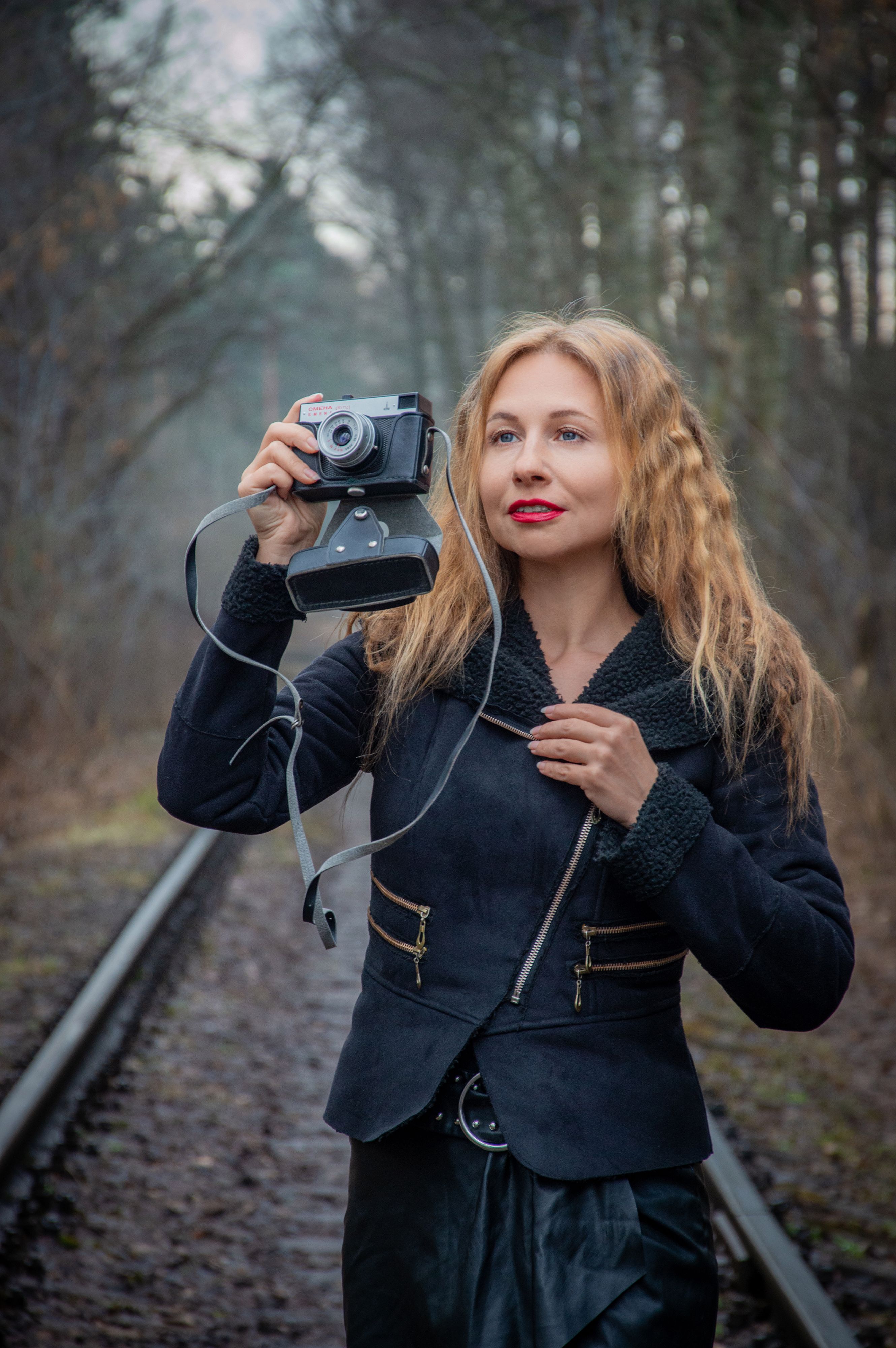 Woman Holding Camera on Forested Railway Tracks · Free Stock Photo