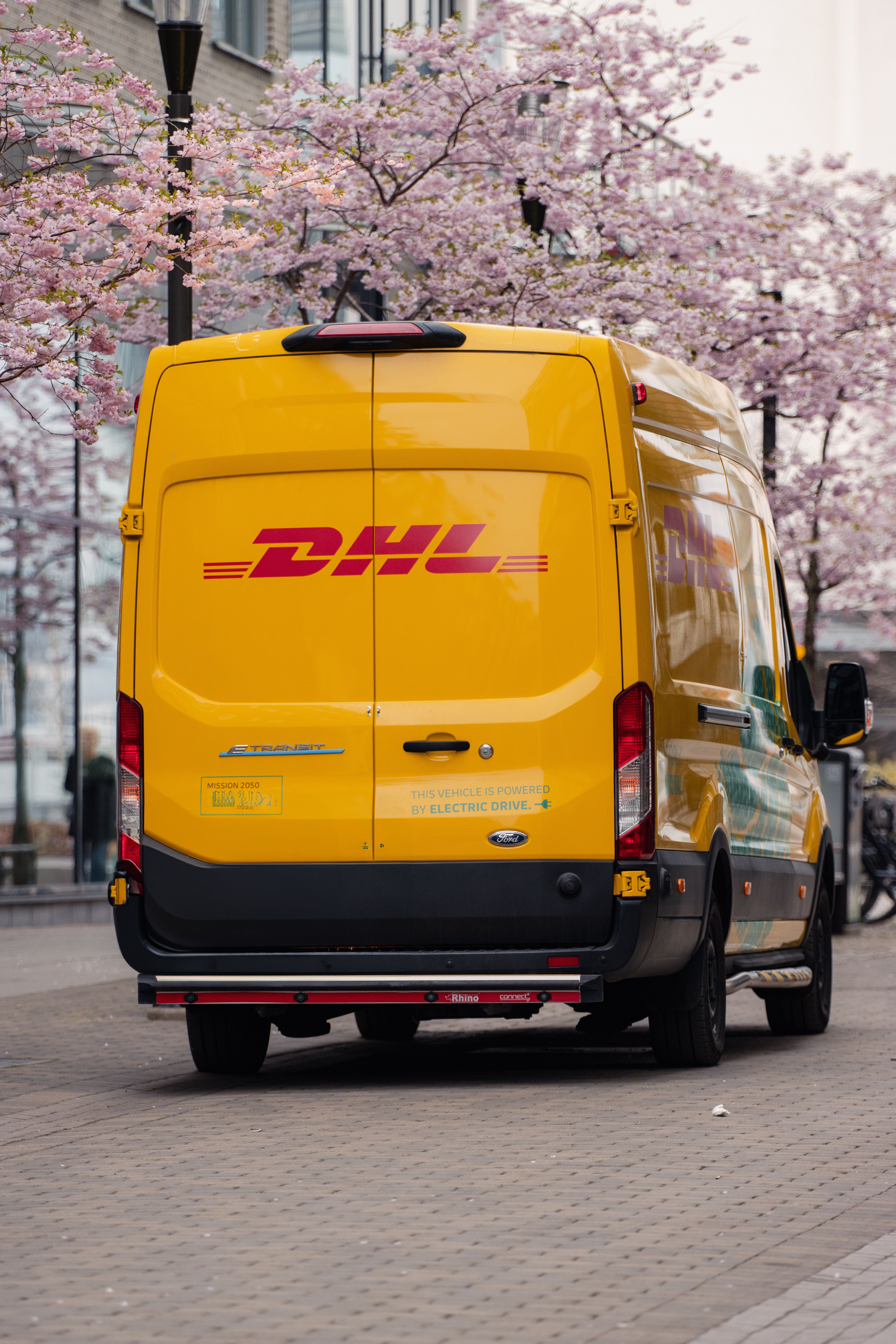 DHL Delivery Van in Cherry Blossom Street Scene · Free Stock Photo