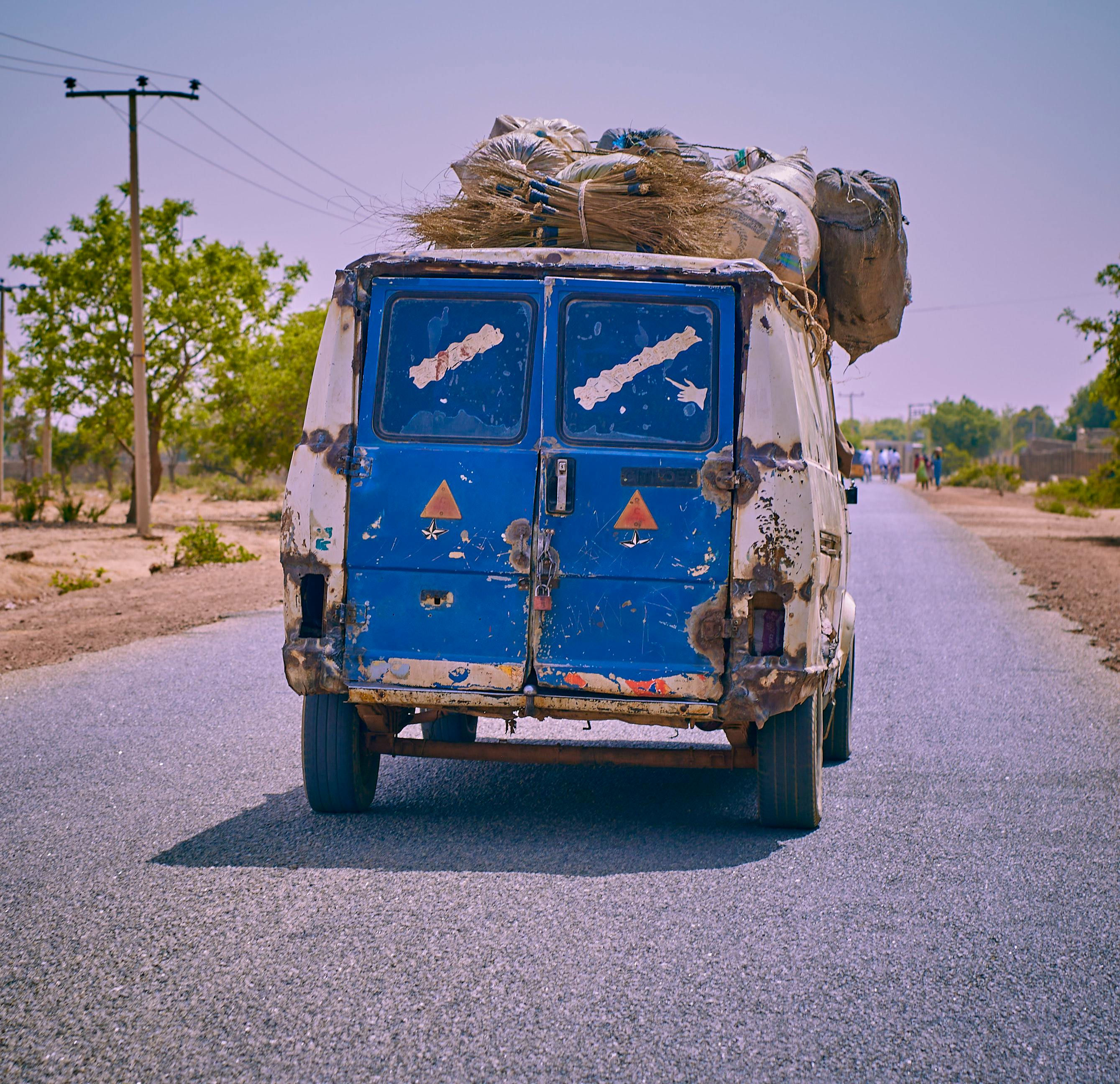 Old Blue Van Loaded with Goods on Rural Road · Free Stock Photo