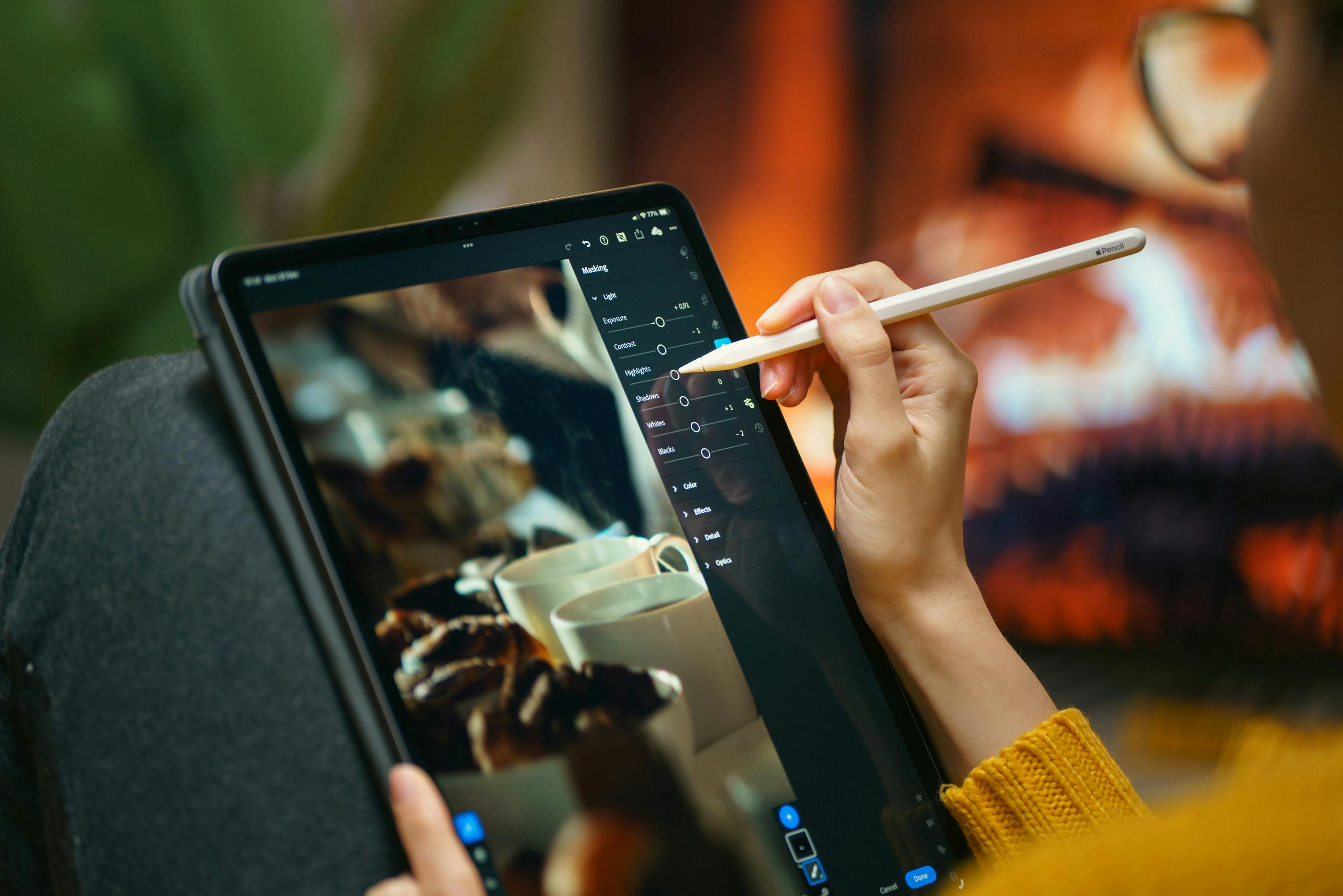 Person Editing Photos on Tablet by Fireplace · Free Stock Photo
