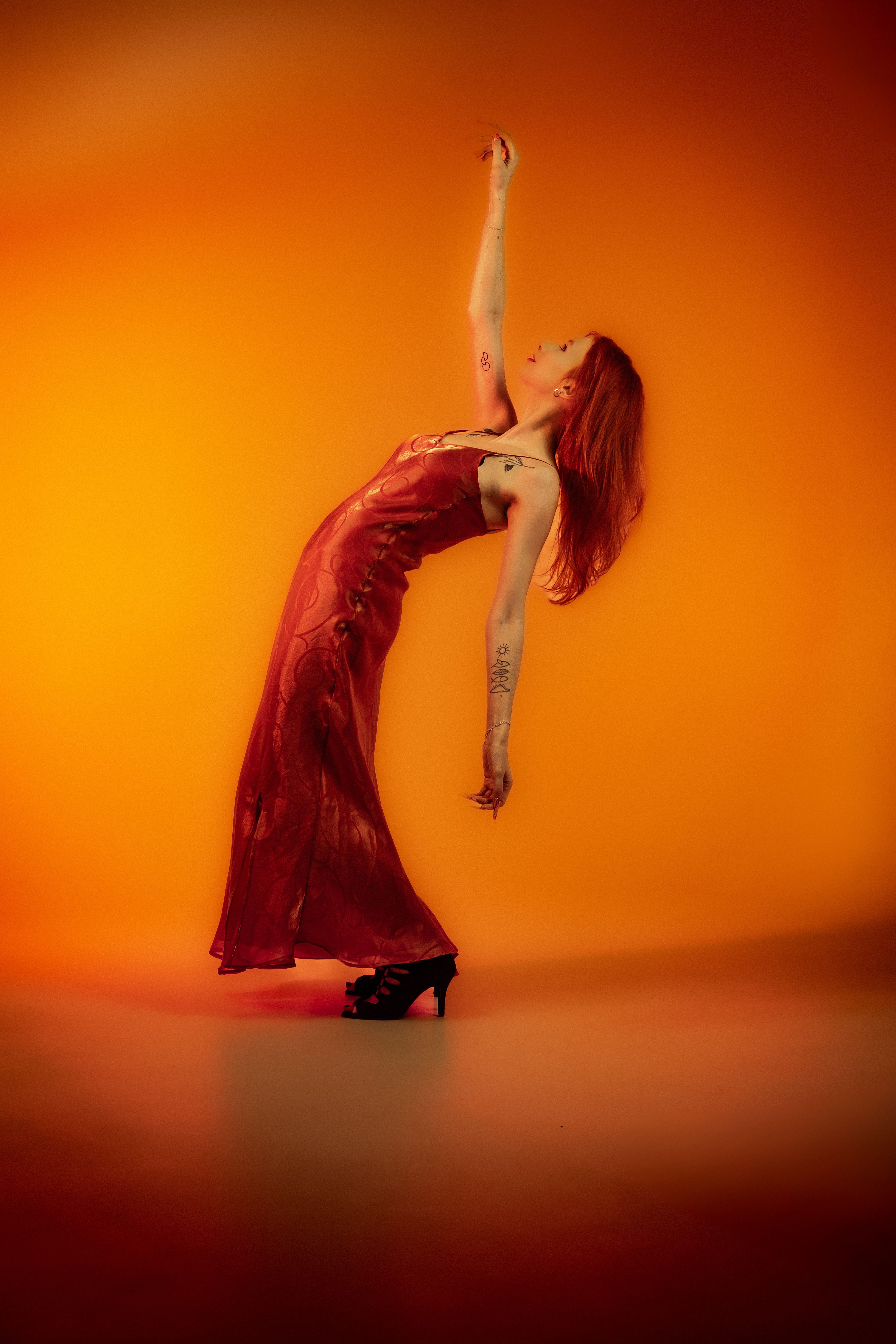 Artistic Female Pose in Vibrant Orange Studio · Free Stock Photo