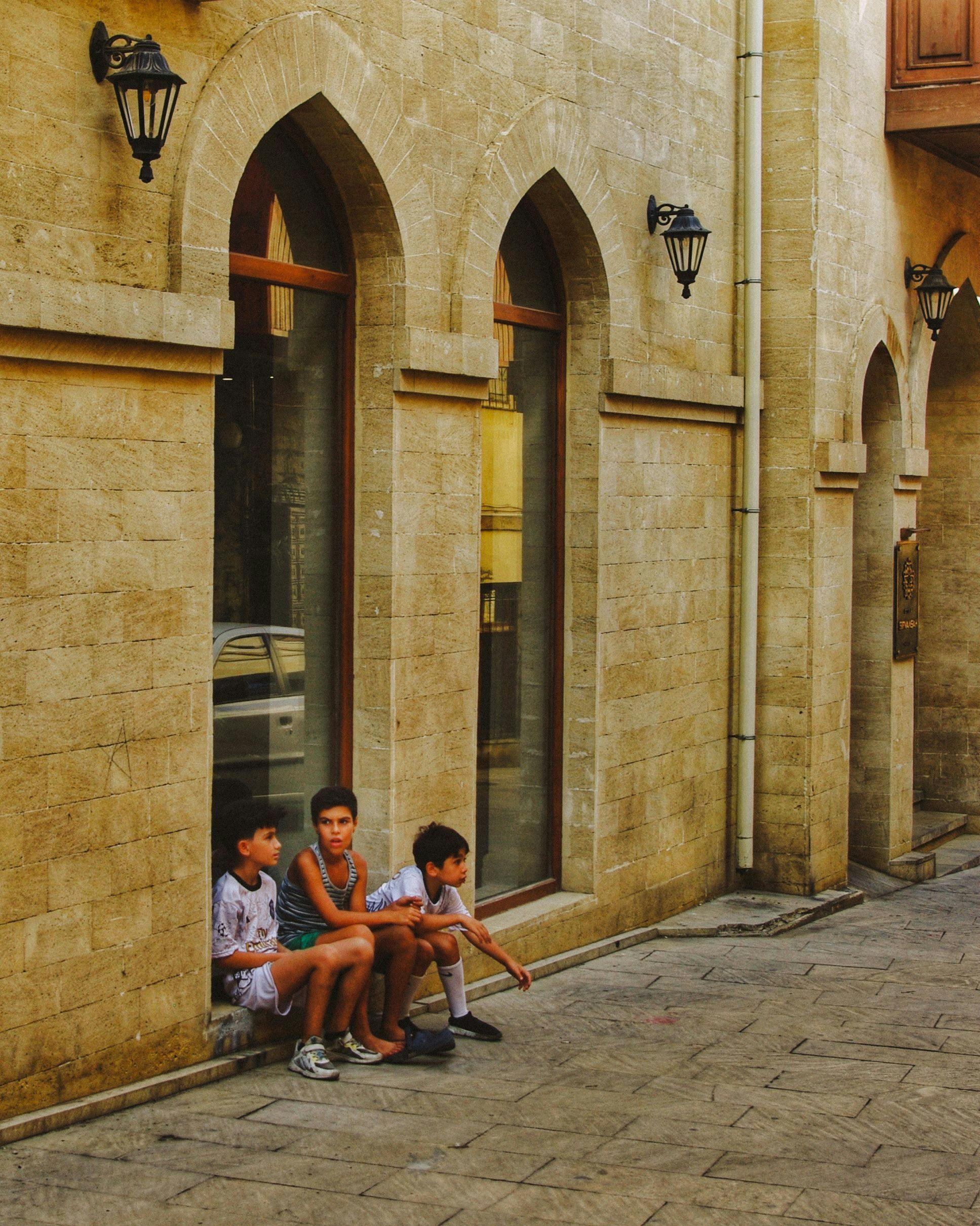 Children Sitting on Sidewalk in Urban Alleyway · Free Stock Photo
