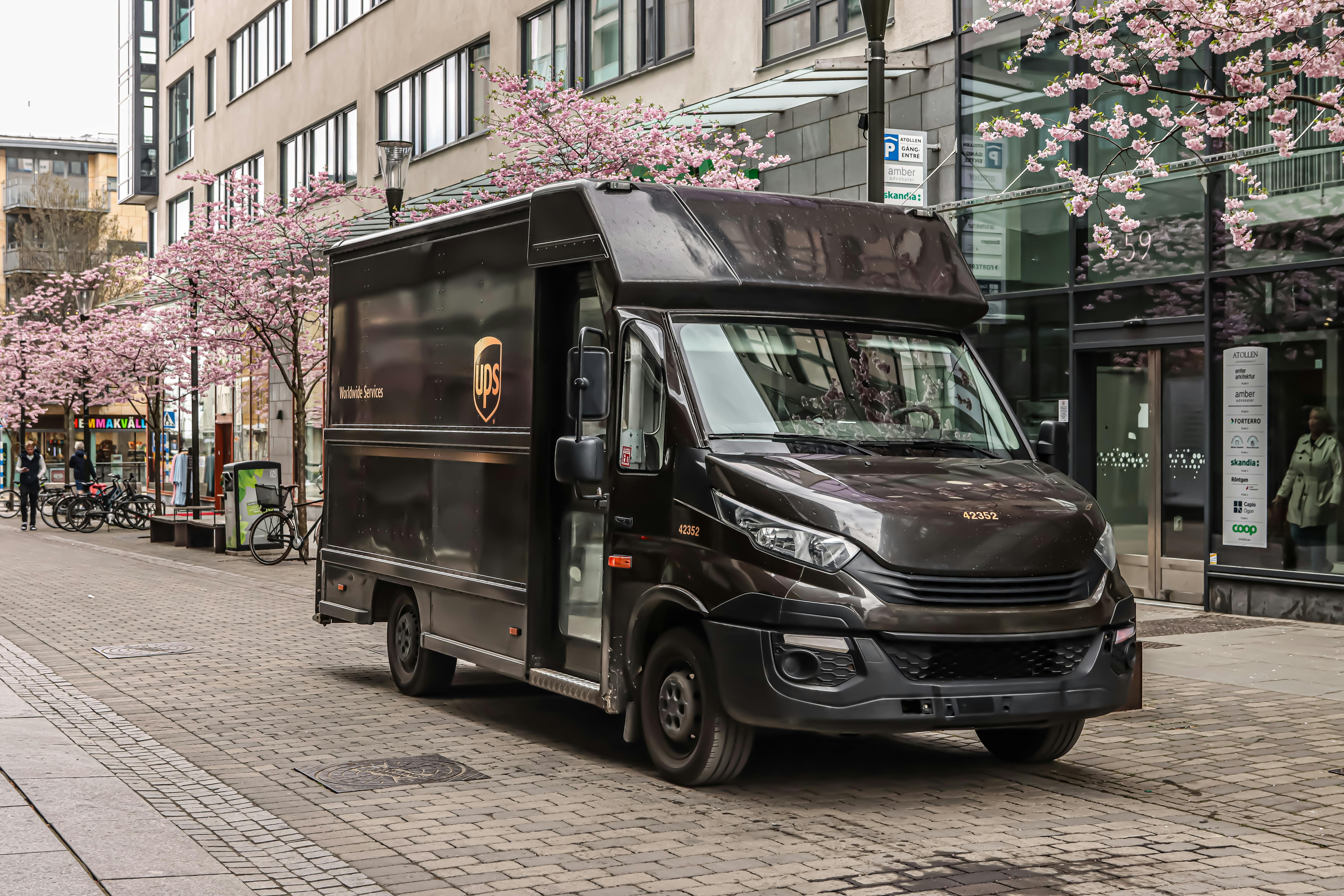 UPS Delivery Truck on Blossom-lined Street in Sweden · Free Stock Photo