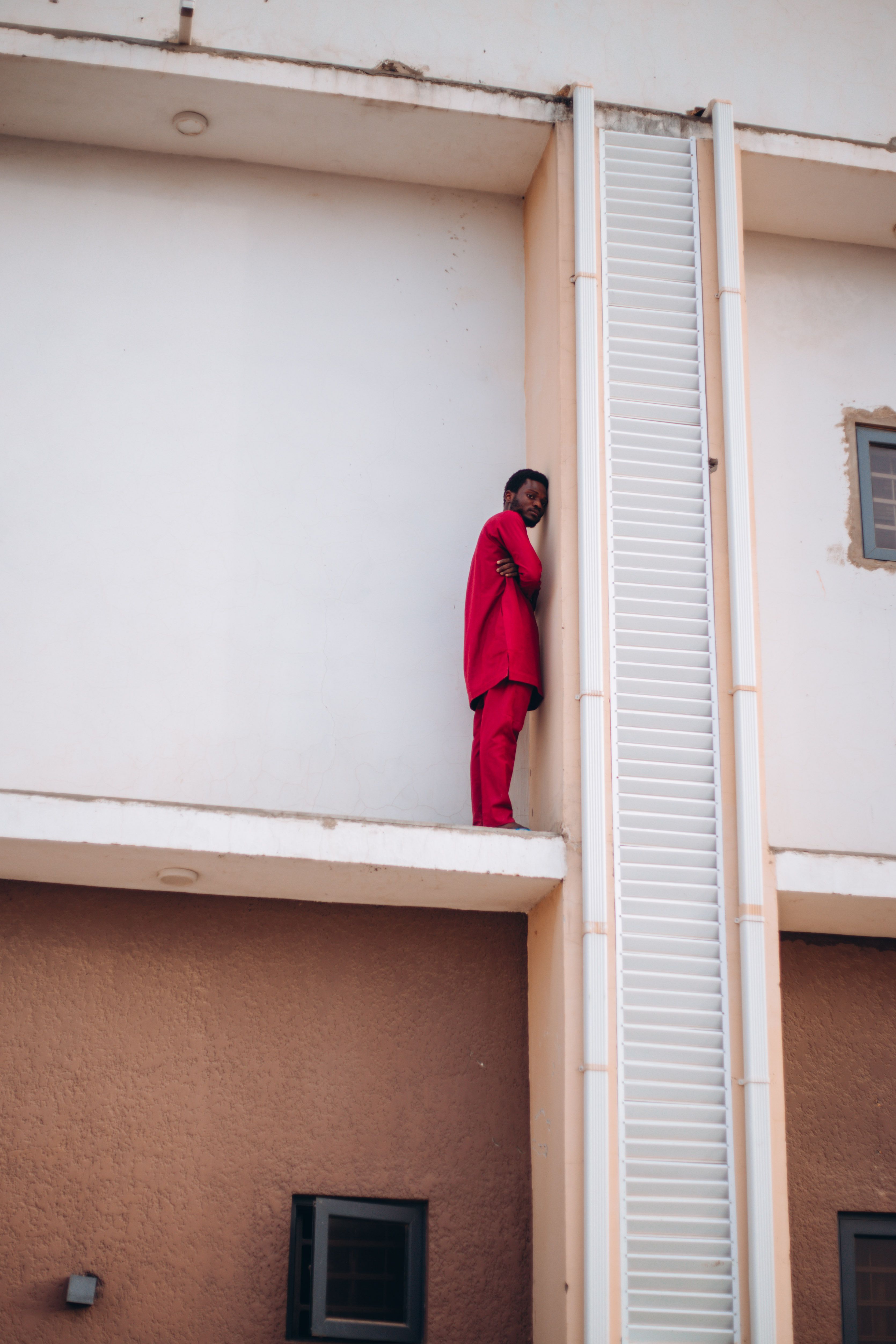 Man Standing Boldly on Building Ledge · Free Stock Photo