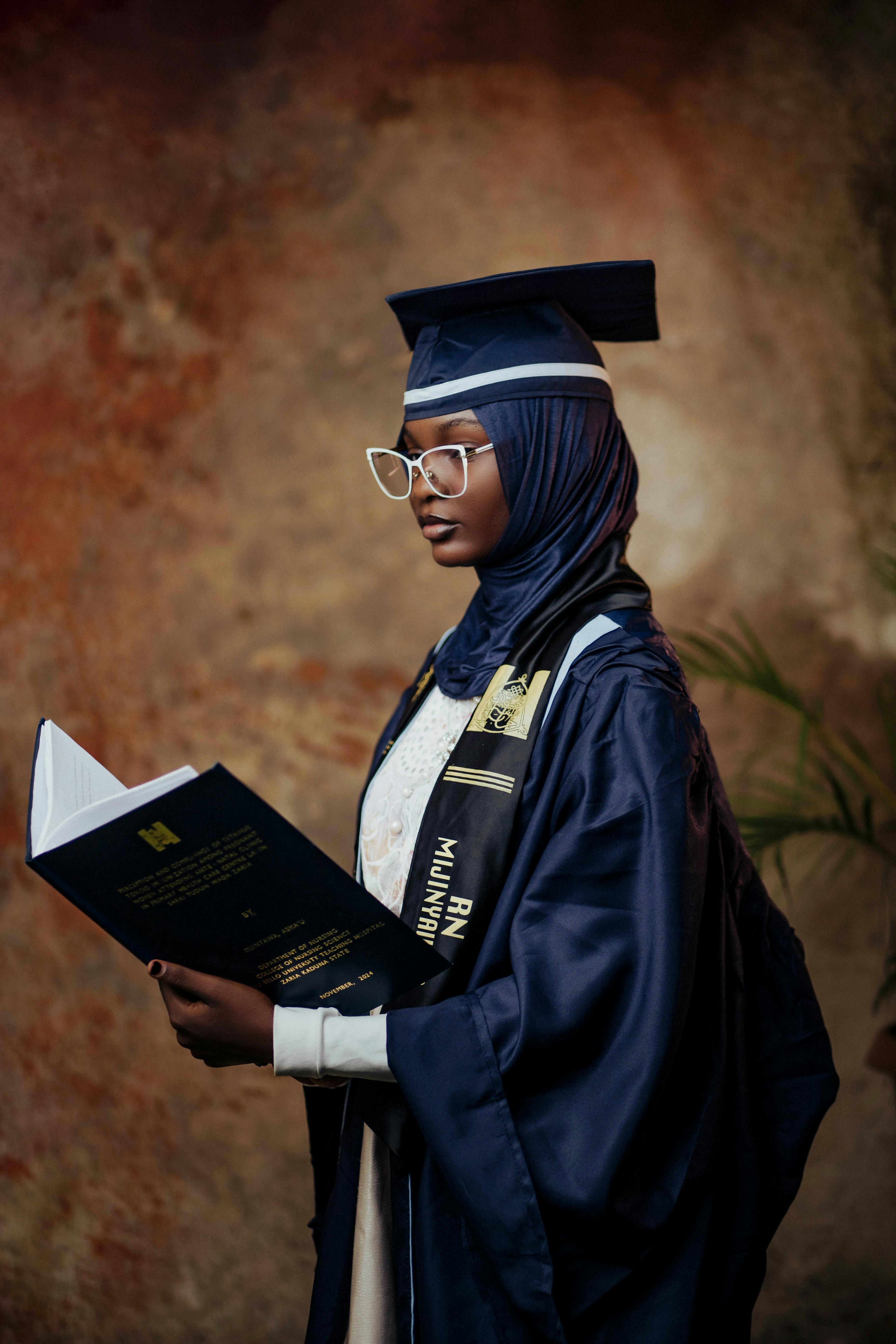 Young Graduate in Cap and Gown Reading Book · Free Stock Photo