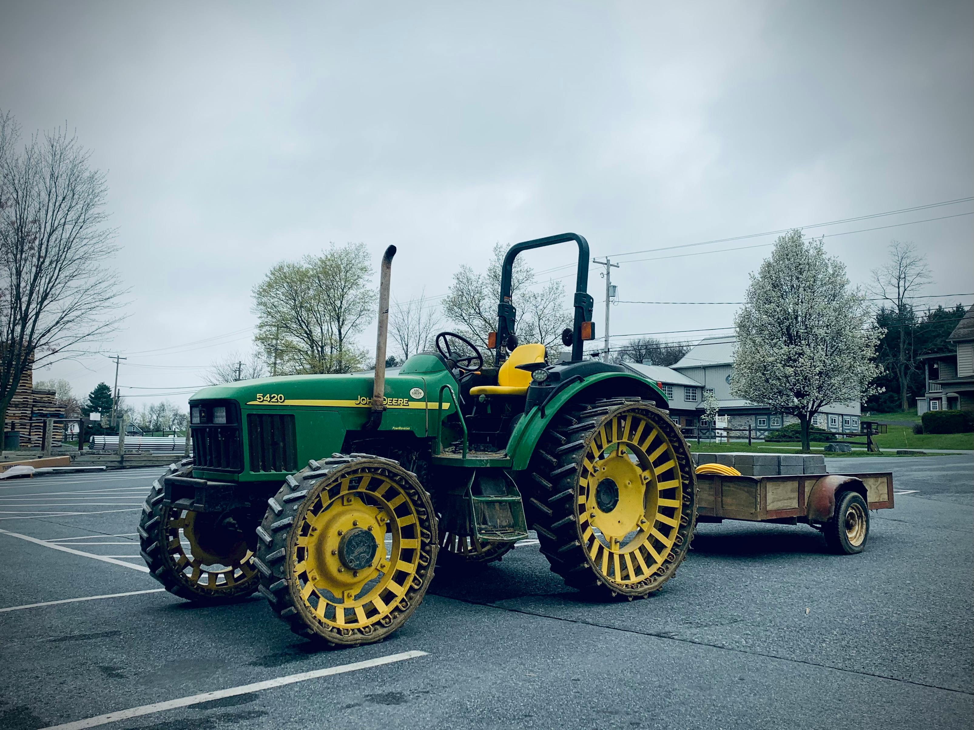 Green Tractor in Parking Lot on Cloudy Day · Free Stock Photo