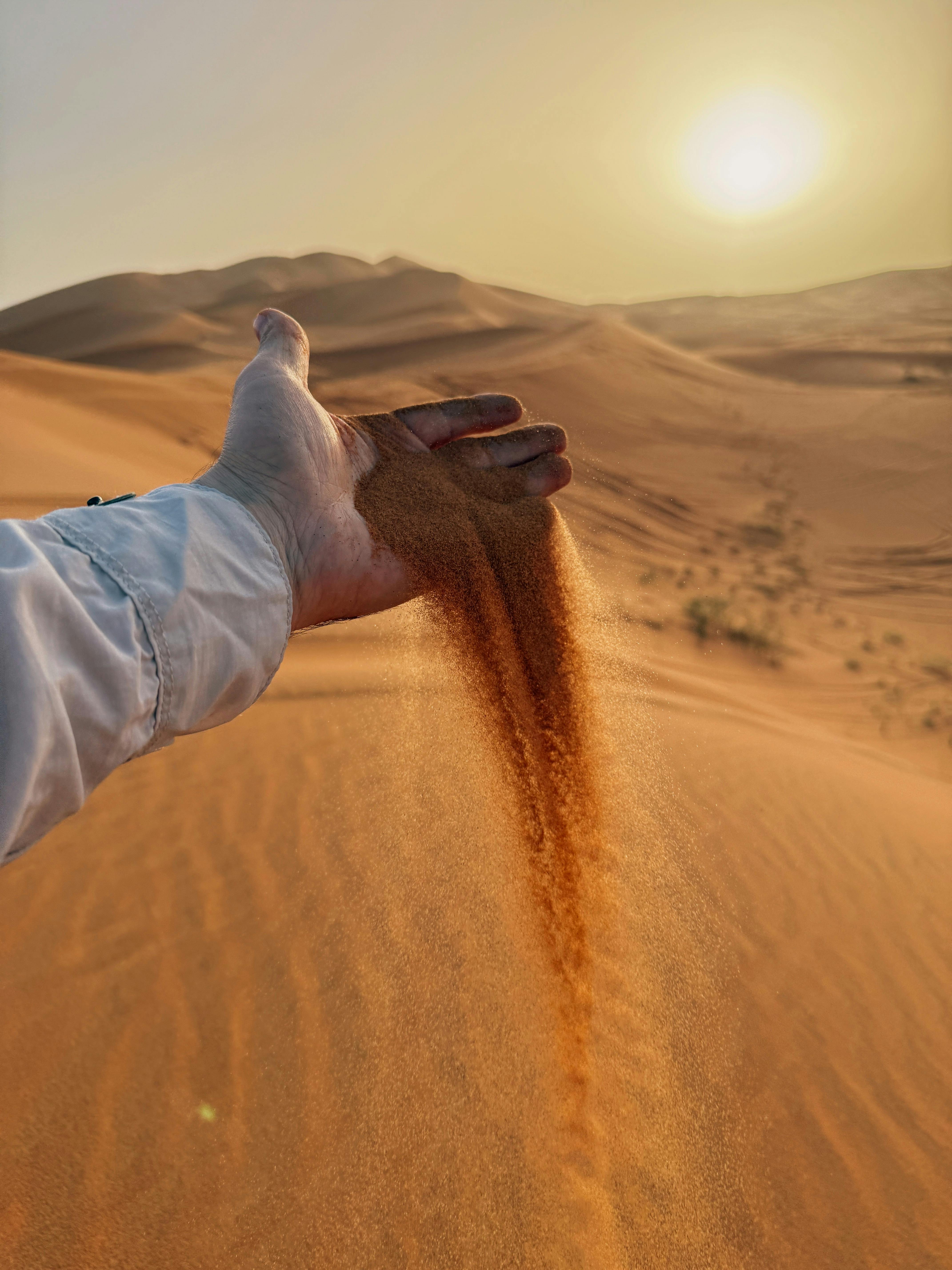 Hand Releasing Sand in Desert Landscape · Free Stock Photo