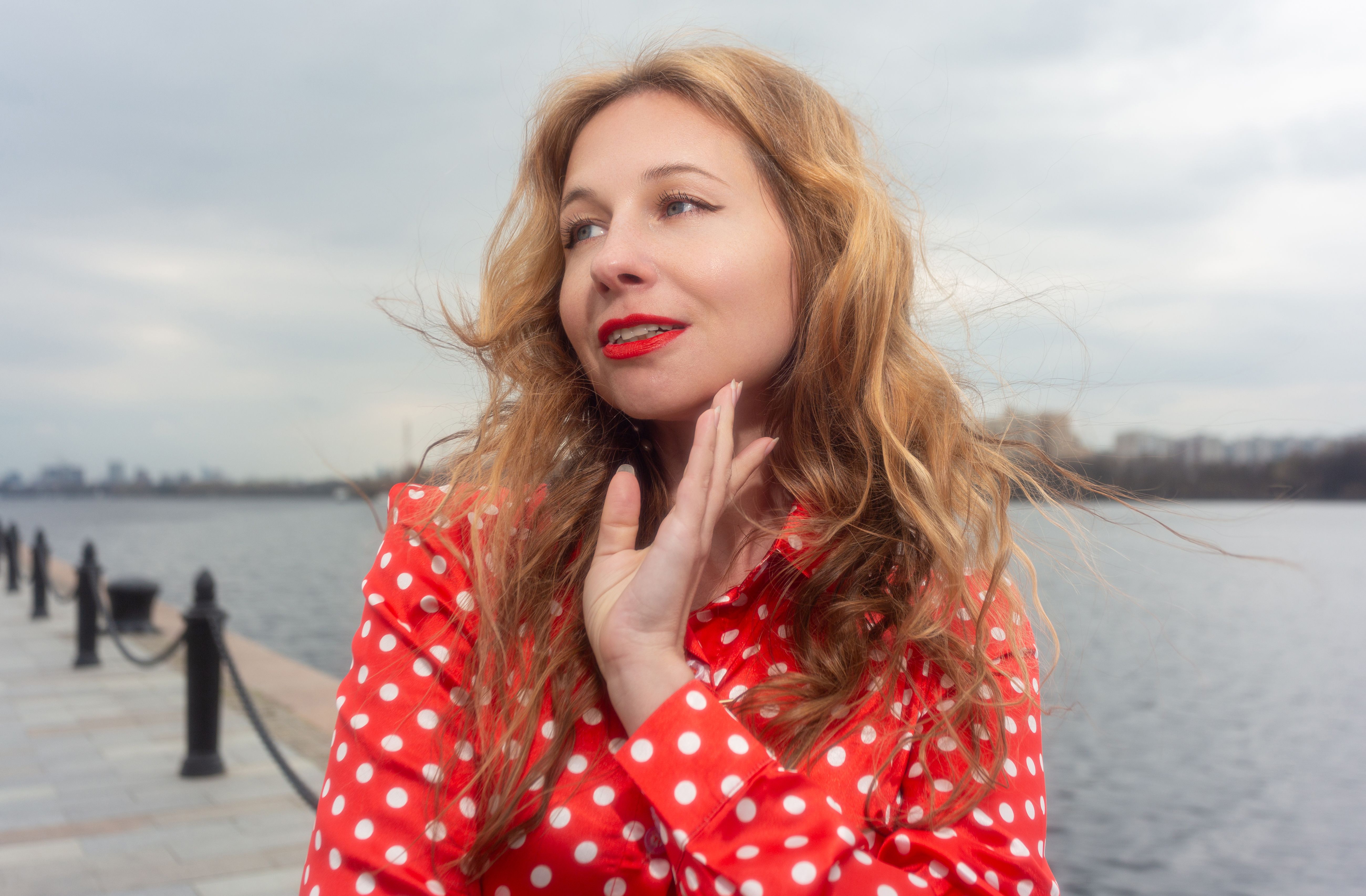Smiling Woman by the Riverside in Red Polka Dot Outfit · Free Stock Photo