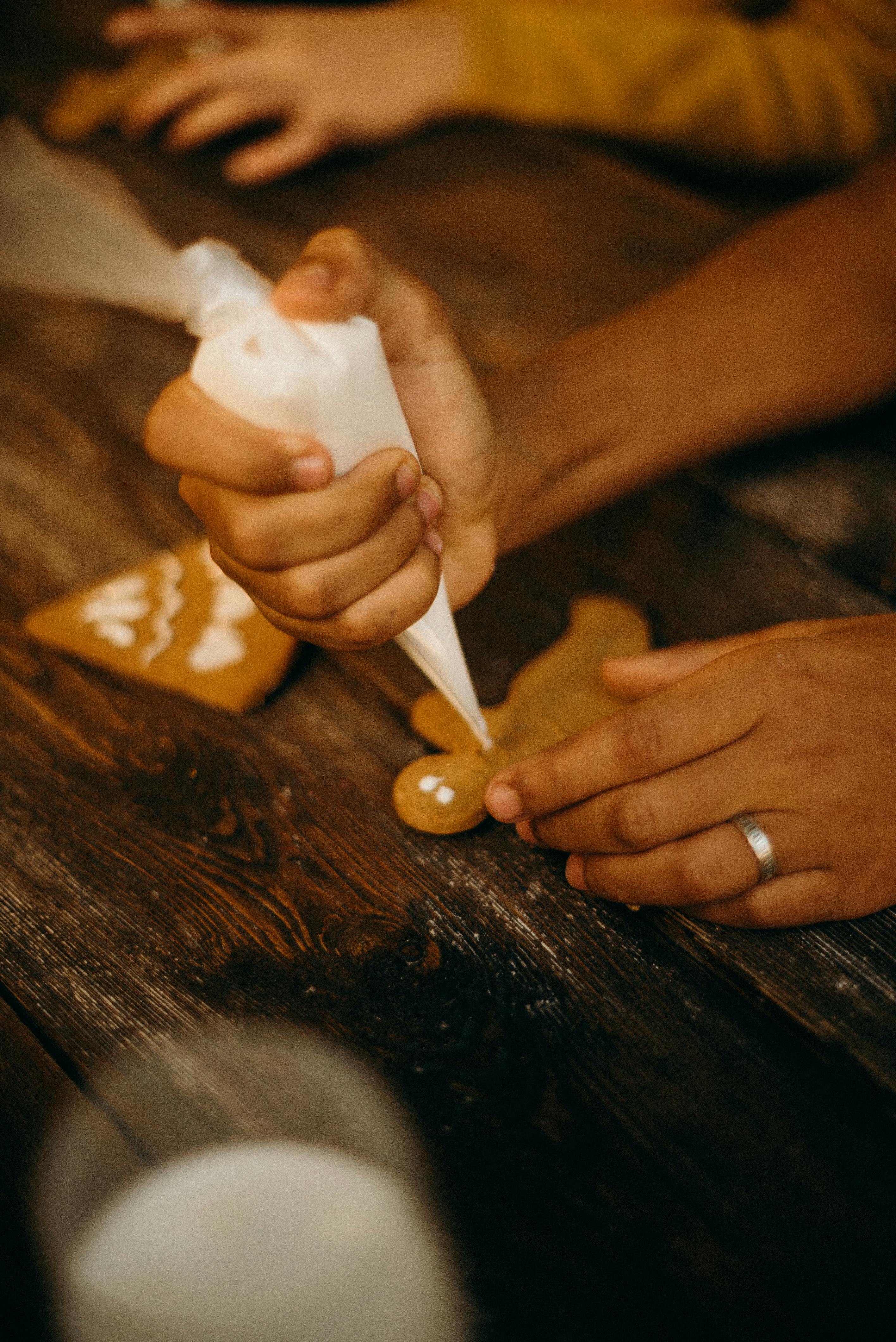 Person Piping Icing on Gingerbread Cookie · Free Stock Photo