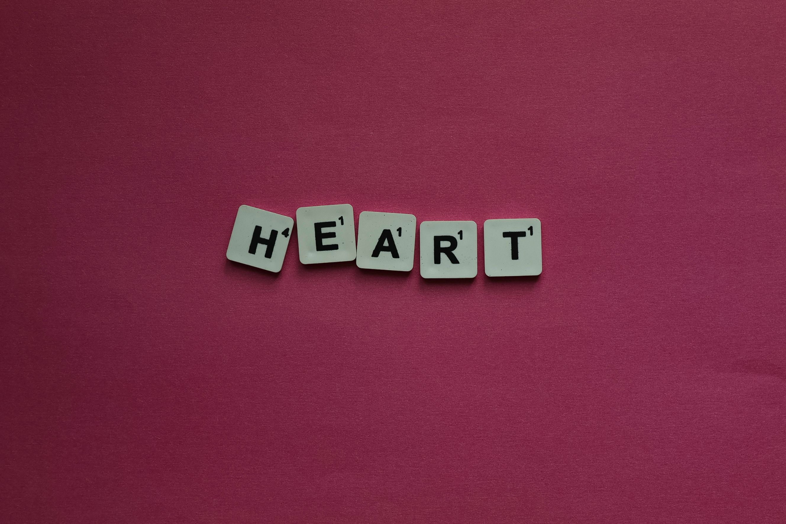 Scrabble Tiles Forming the Word Heart on Pink Background · Free Stock Photo