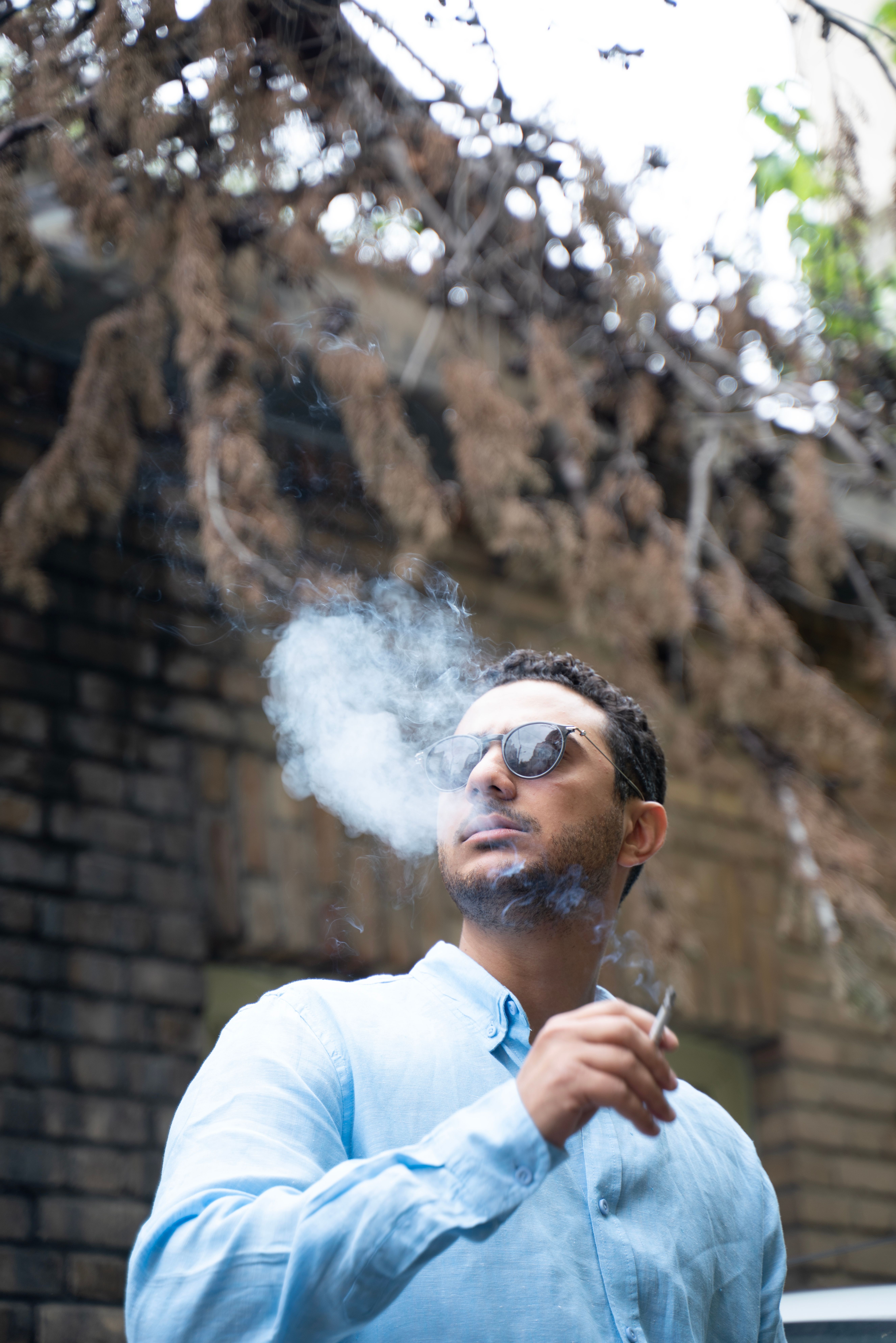 Stylish Man Smoking Outdoors in Sunglasses · Free Stock Photo