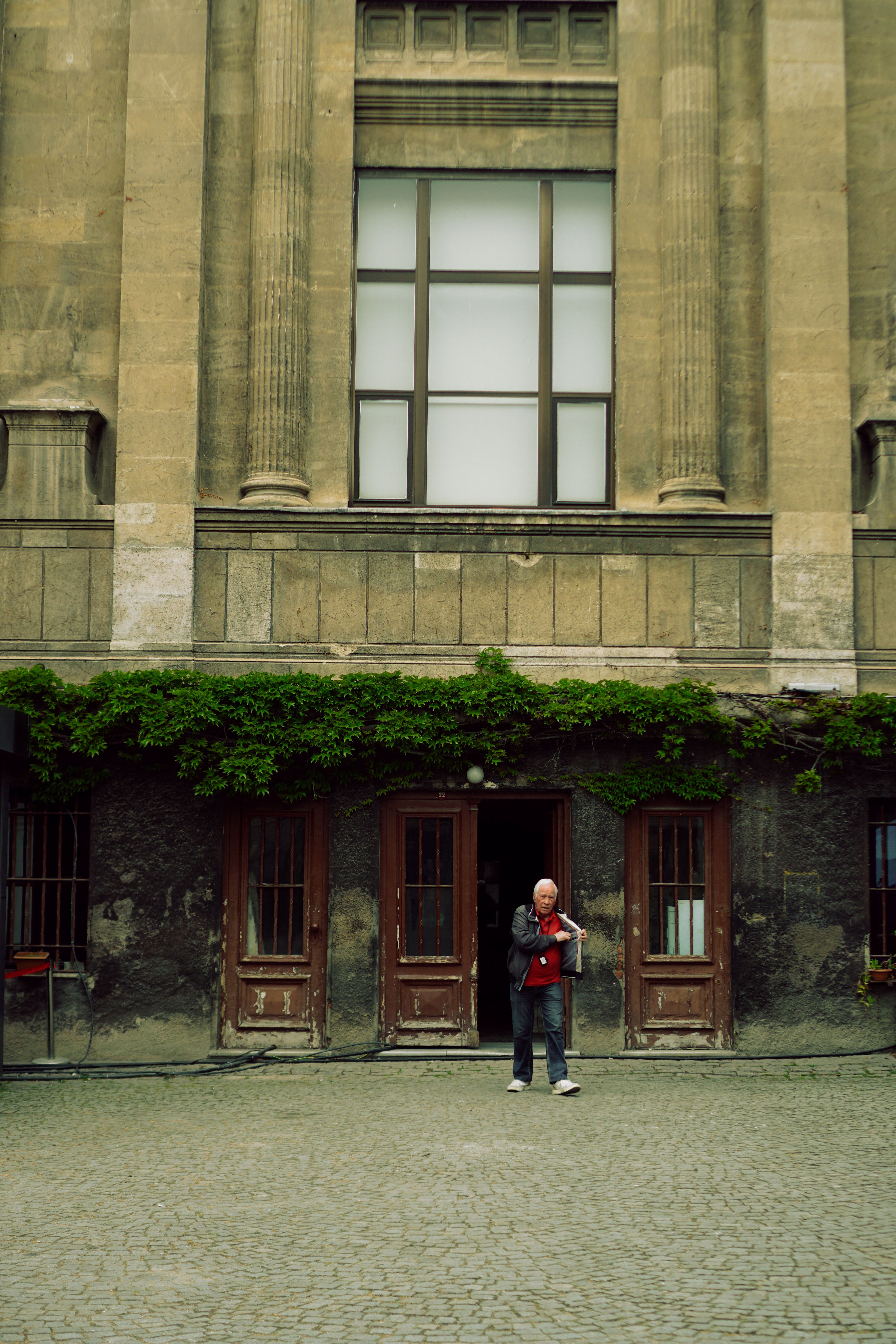 Elderly Man Outside Historic Building with Ivy · Free Stock Photo