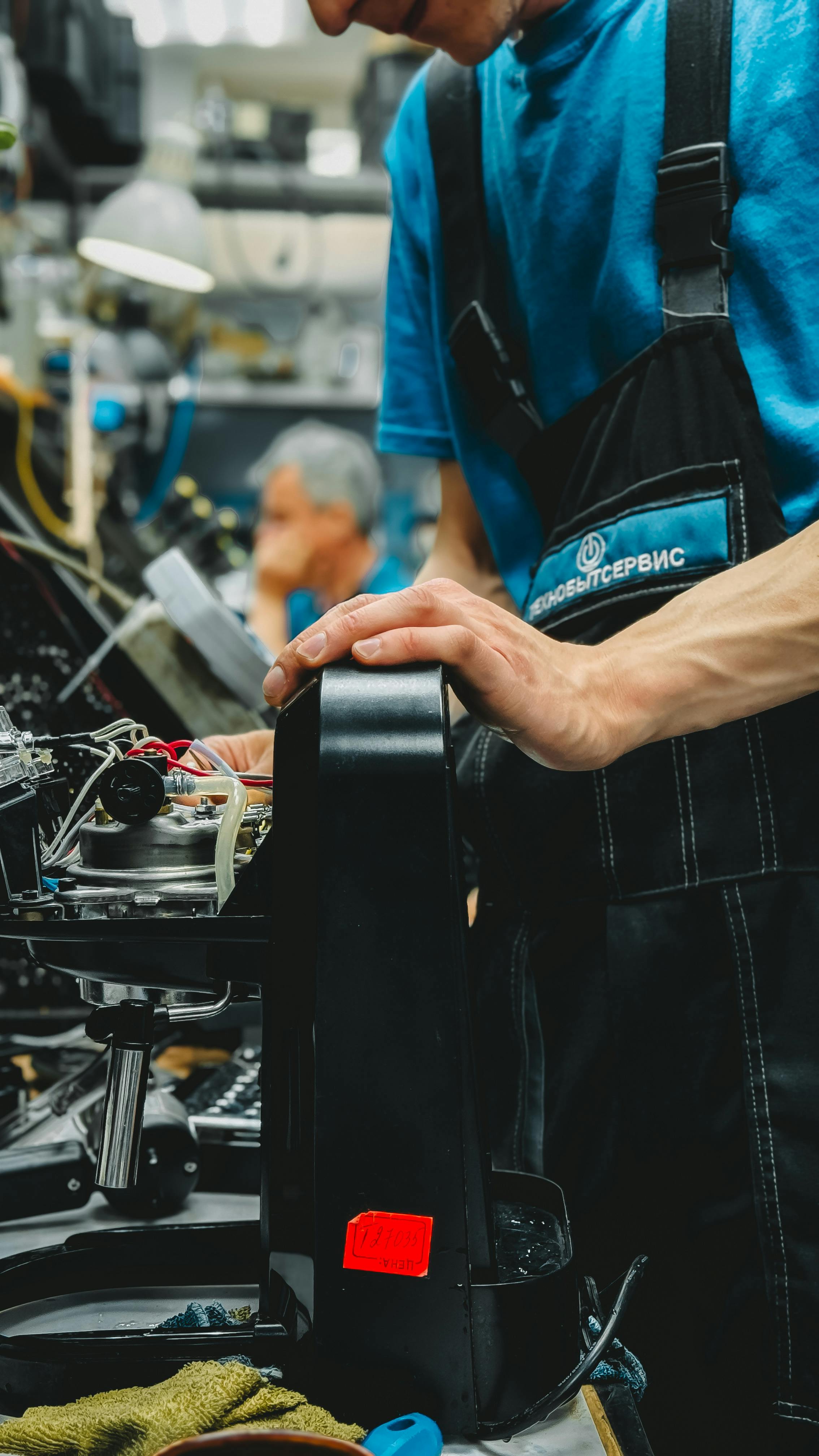 Technician Repairing Coffee Machine in Workshop · Free Stock Photo