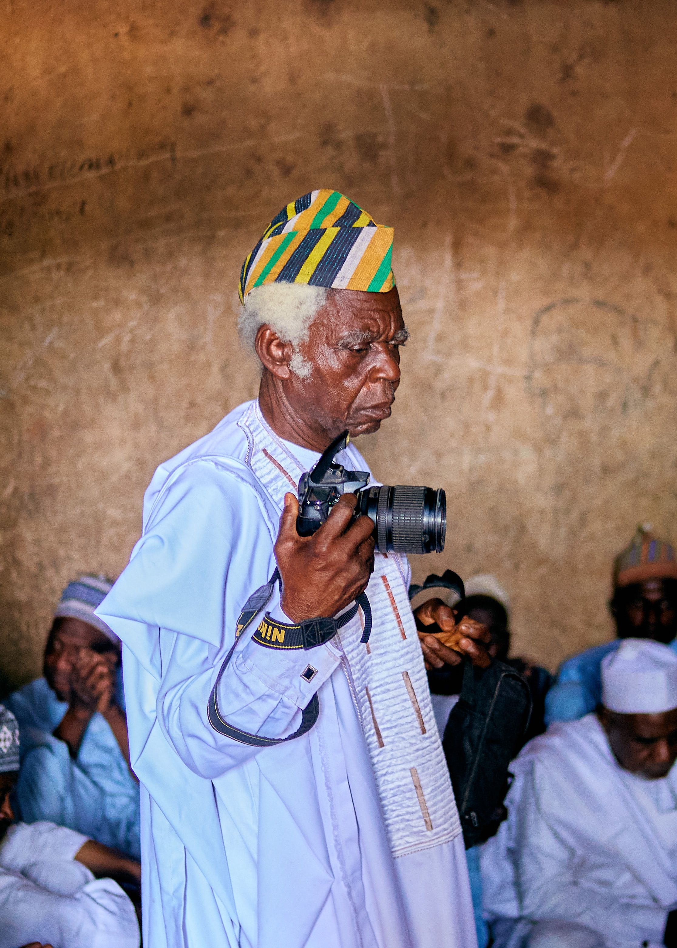 Elderly Photographer with Camera in Indoor Setting · Free Stock Photo