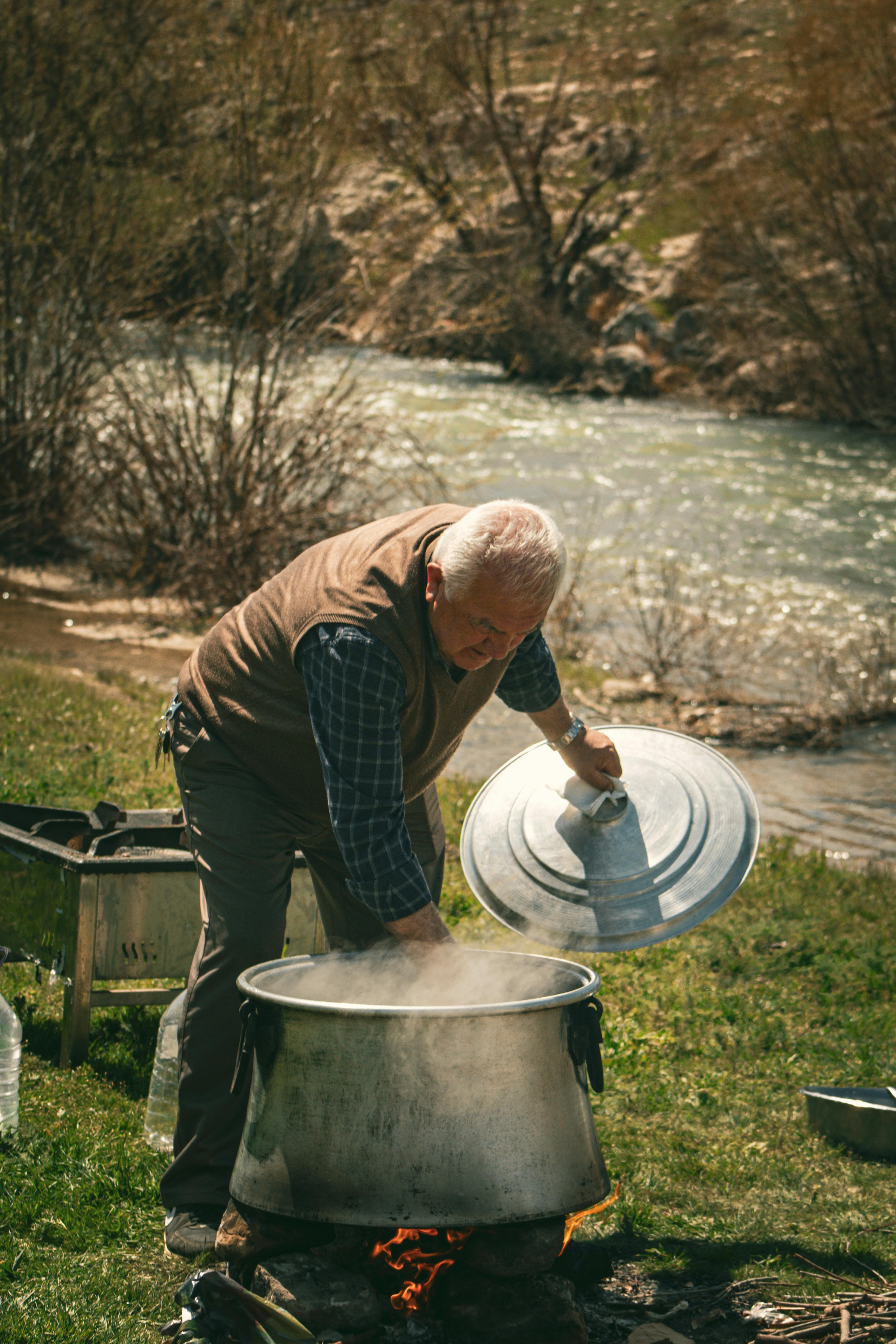 Senior man cooking outdoors by river in Kahramanmaraş · Free Stock Photo