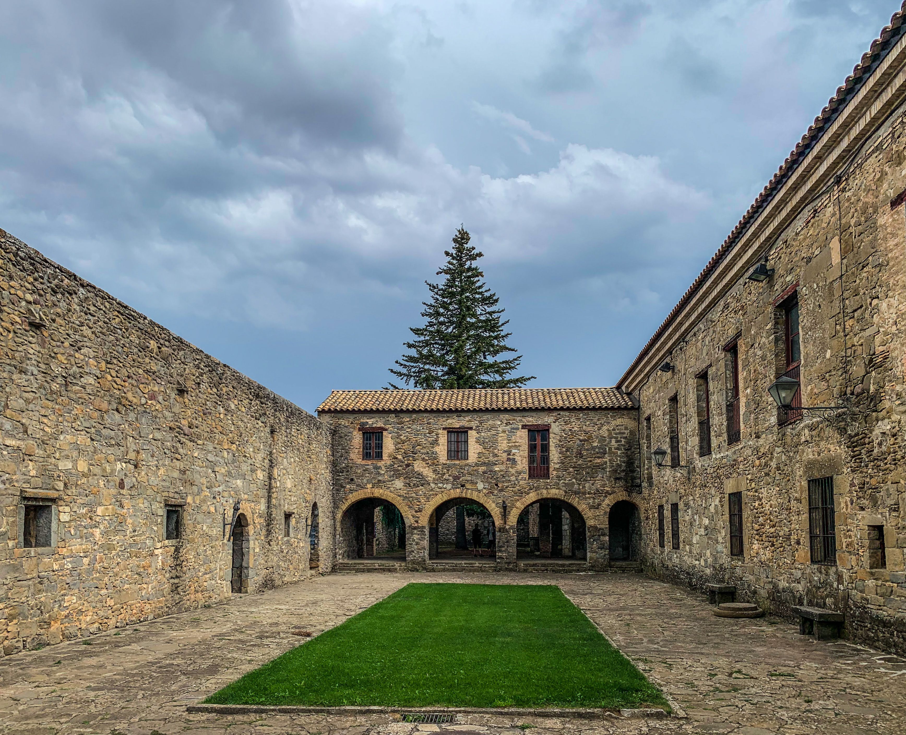 Historic Stone Courtyard with Arches and Green Lawn · Free Stock Photo
