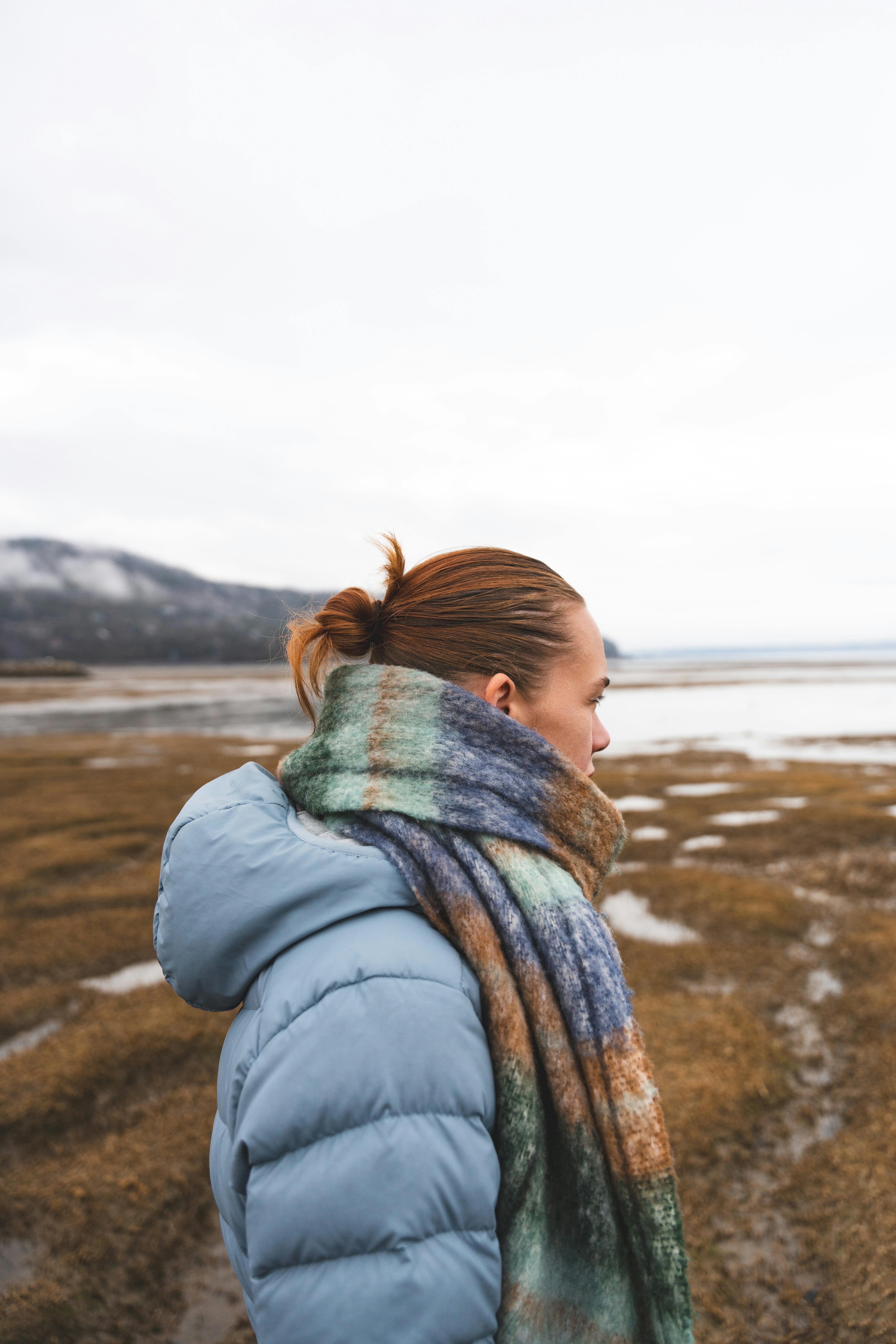 Woman in Cozy Scarf Enjoys Scenic Beach View · Free Stock Photo