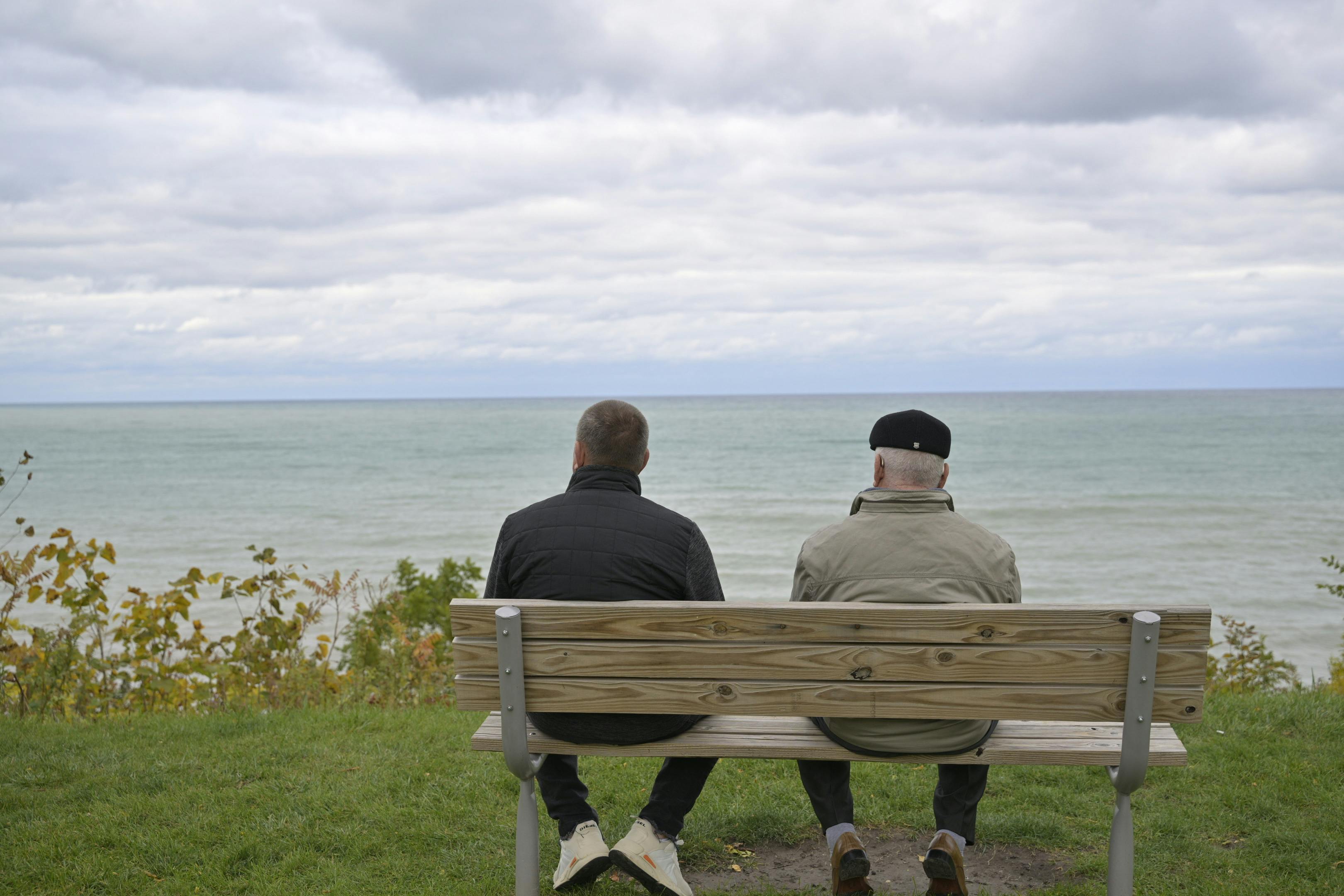 Two Men on Bench Overlooking Tranquil Ocean · Free Stock Photo