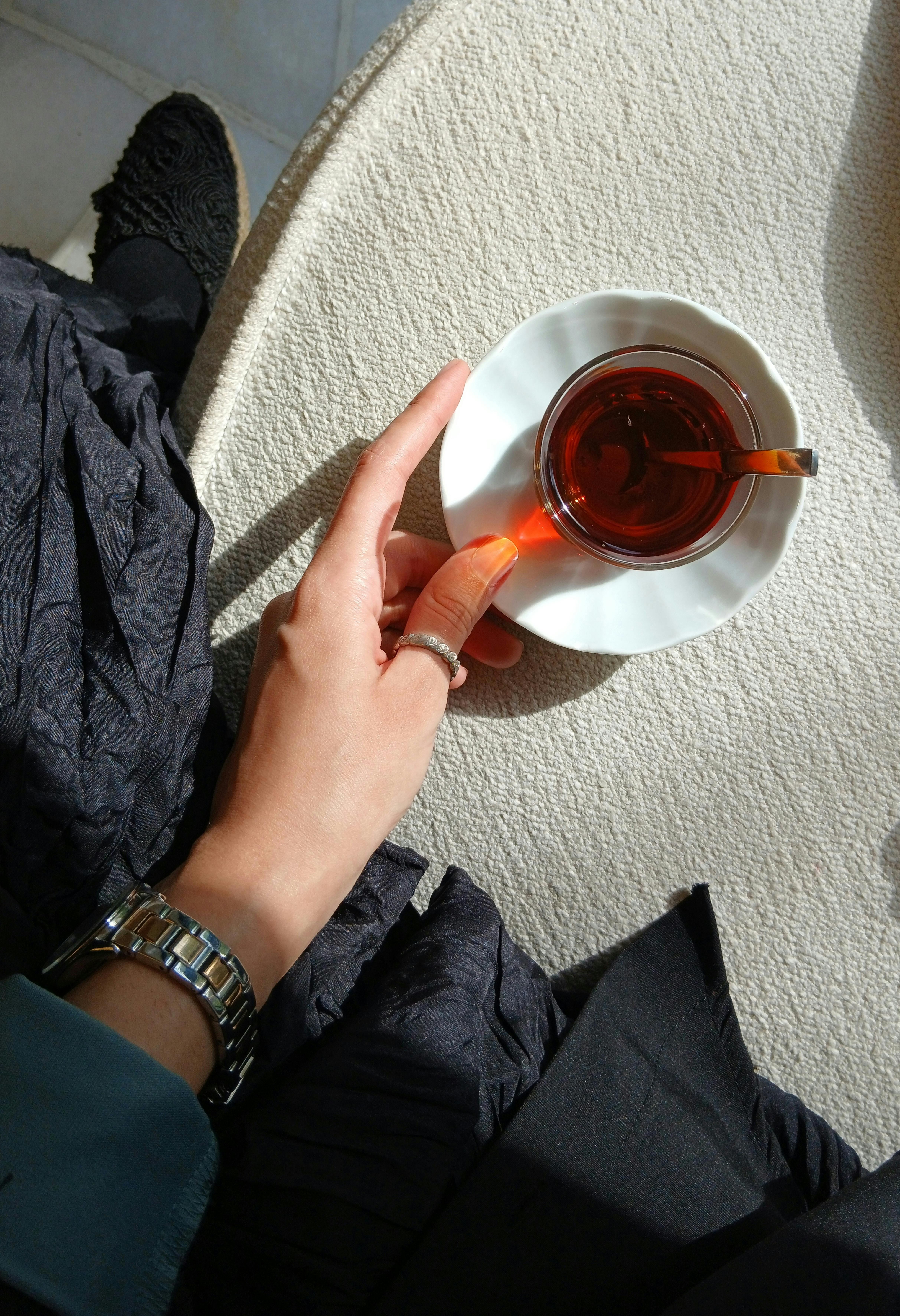 Elegant Hand Holding Tea Cup in Sunlight · Free Stock Photo