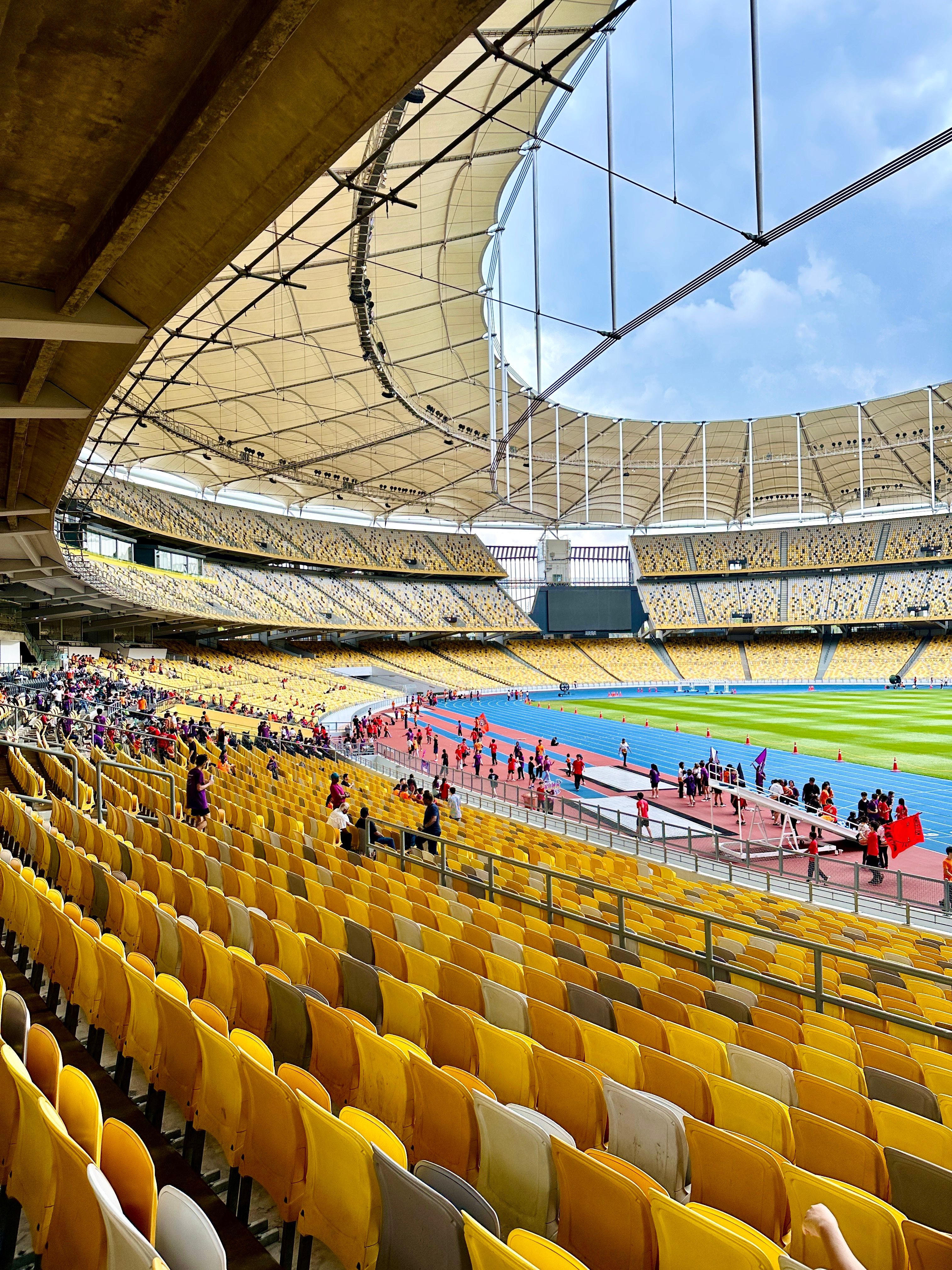 Vibrant stadium with yellow seating and blue track · Free Stock Photo