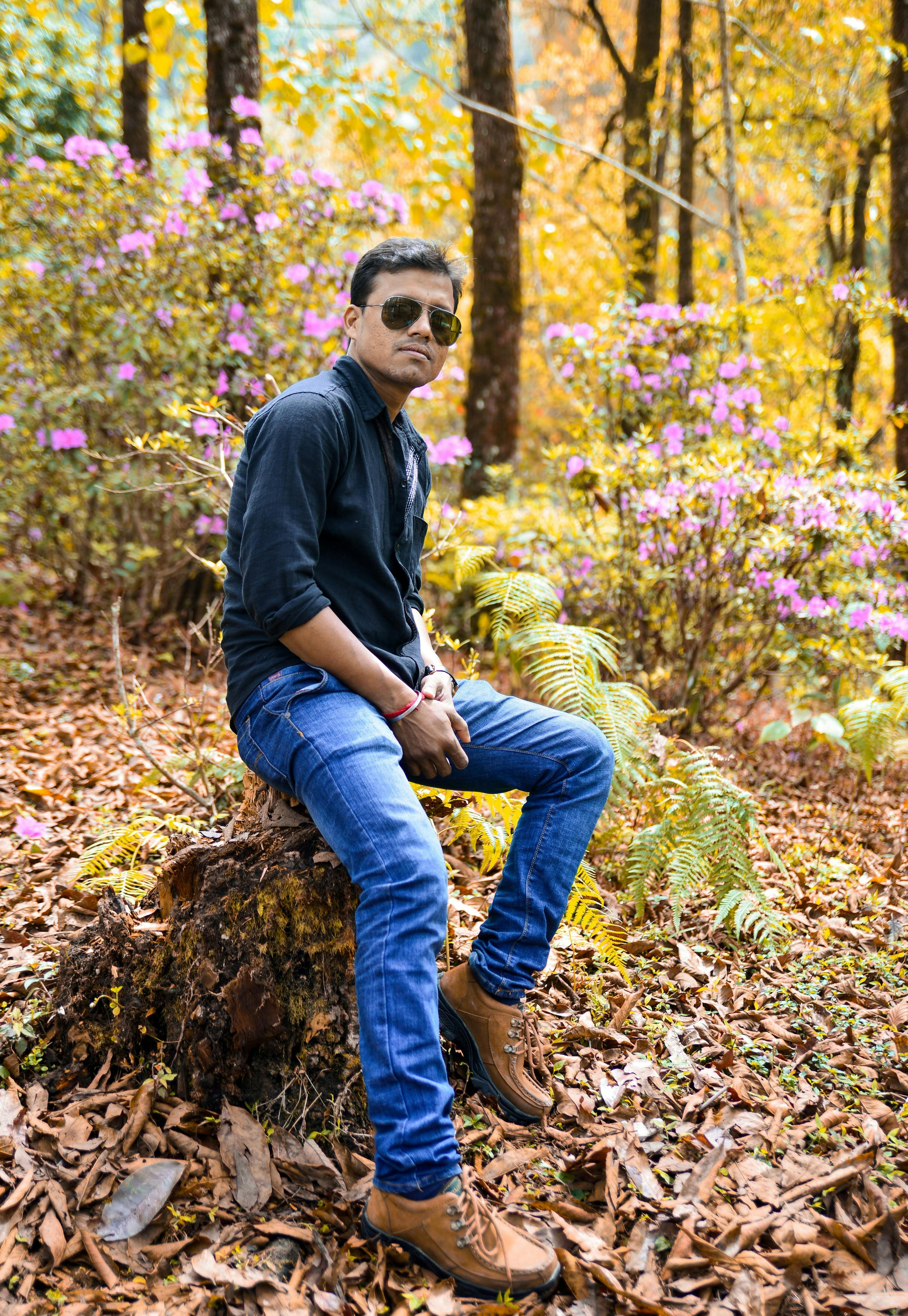 Young Man Sitting on Tree Stump in Forest · Free Stock Photo
