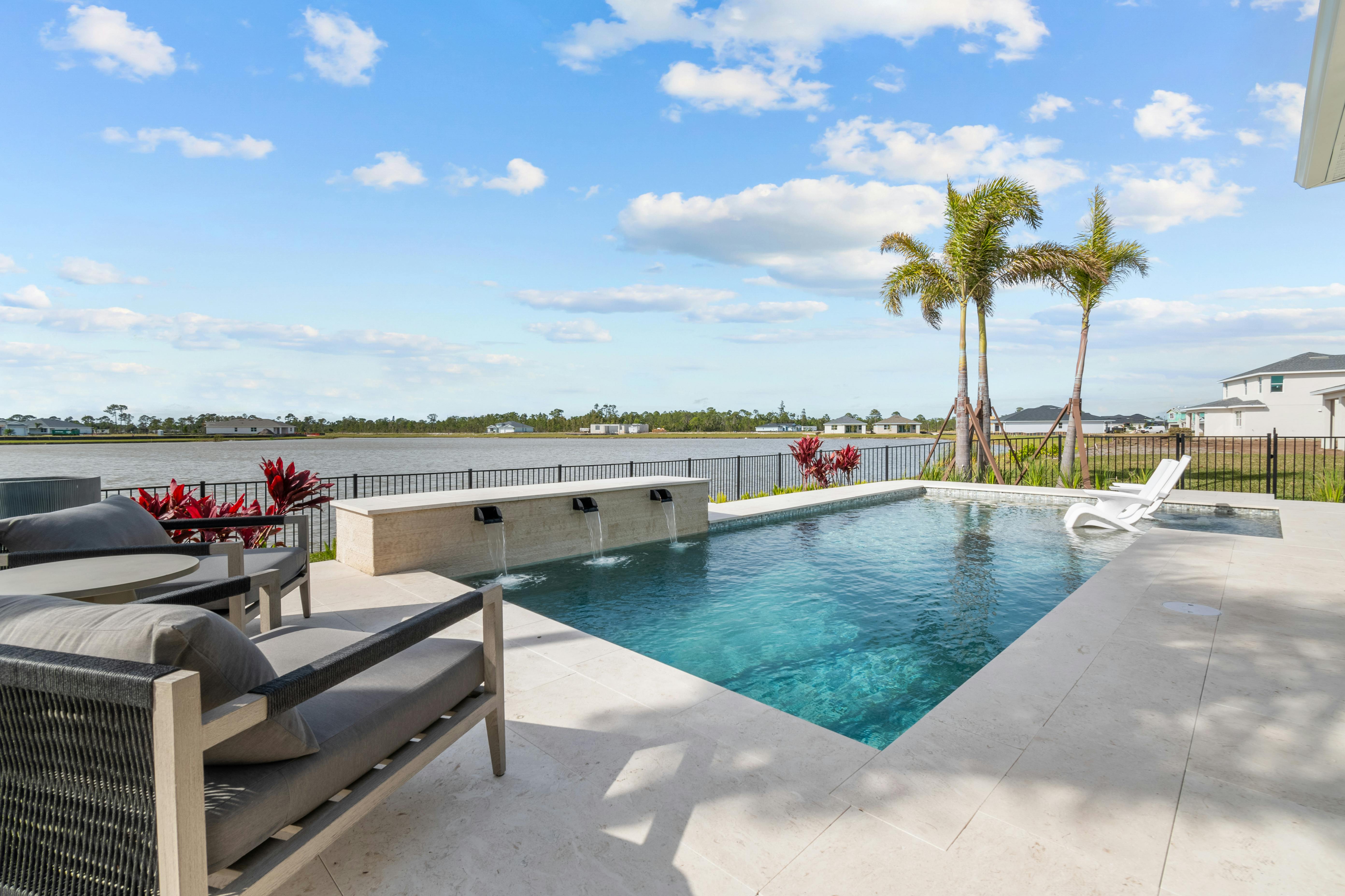 Luxurious Poolside View with Palm Trees and Lake · Free Stock Photo
