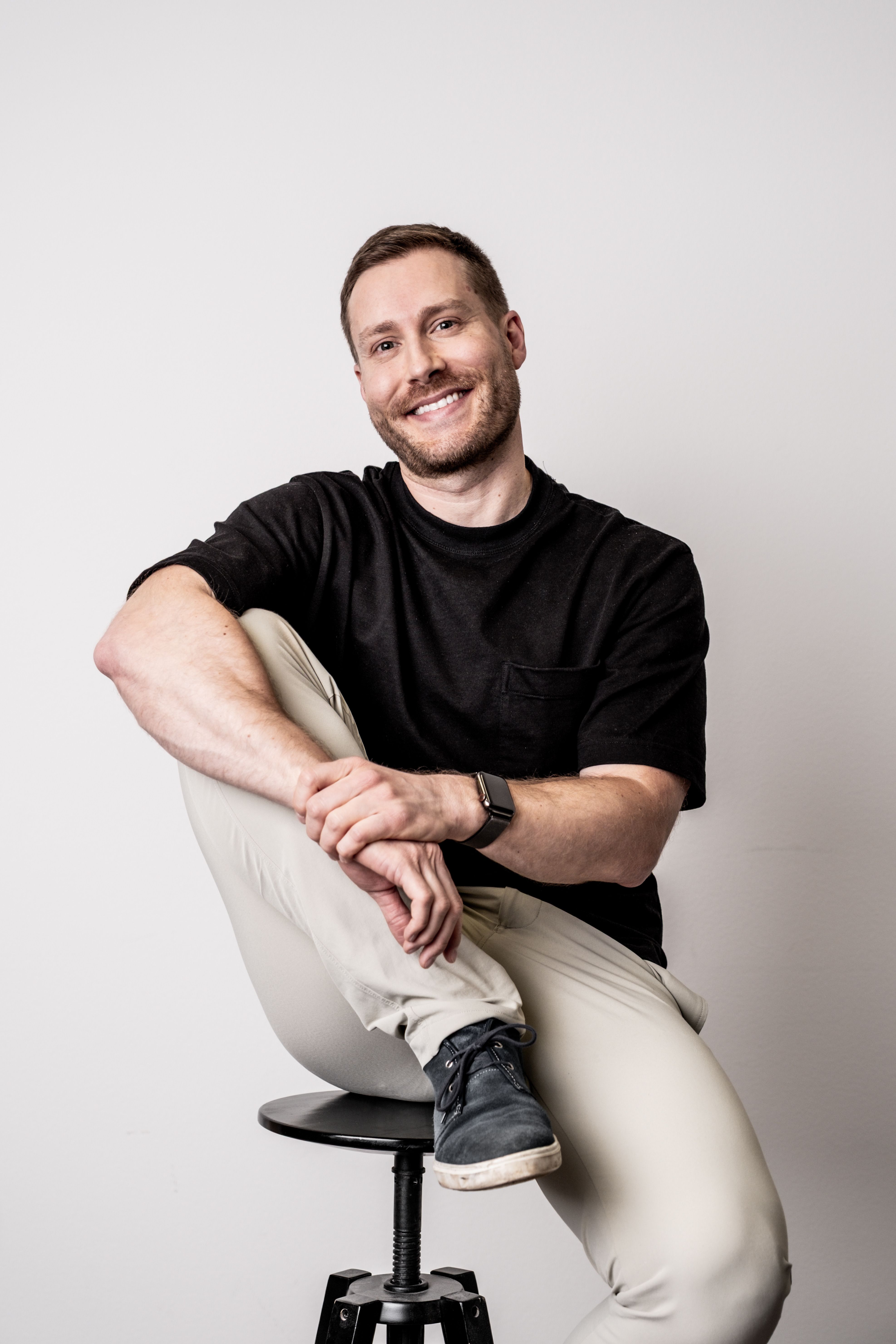 Casual portrait of smiling man seated on stool · Free Stock Photo