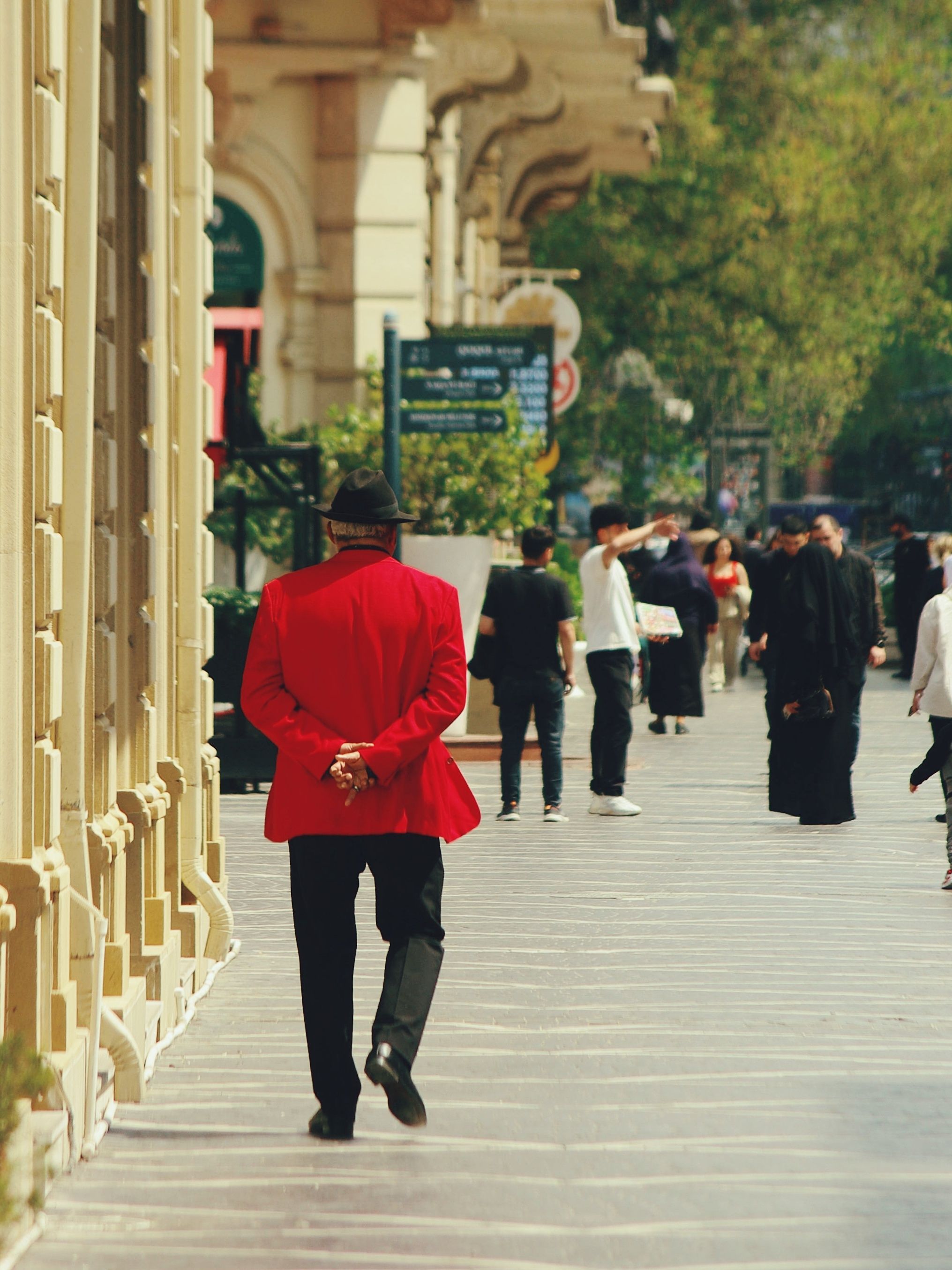 Man in Red Jacket Walking on Lively City Street · Free Stock Photo