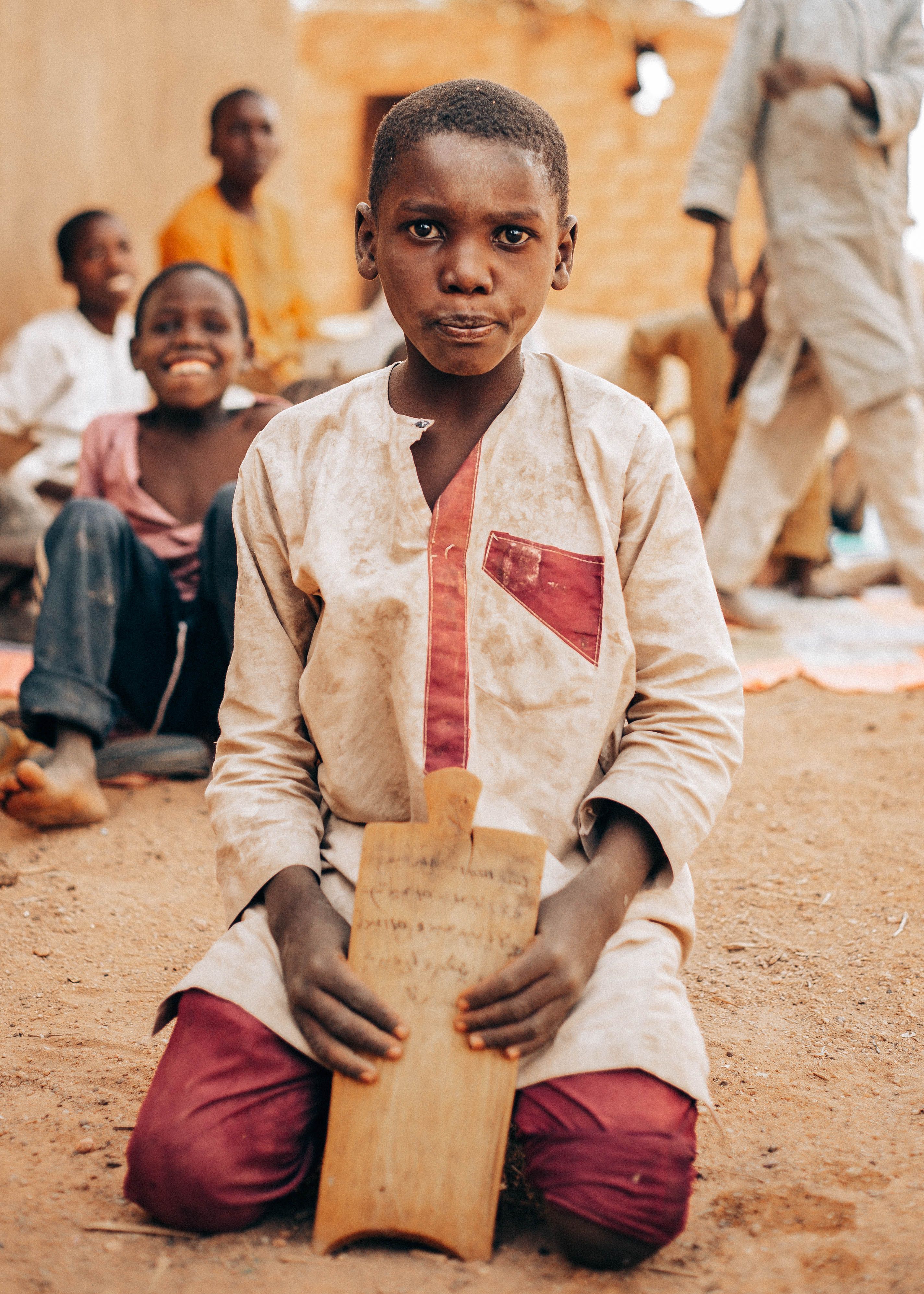 African Child Holding Handmade Wooden Tablet Outdoors · Free Stock Photo