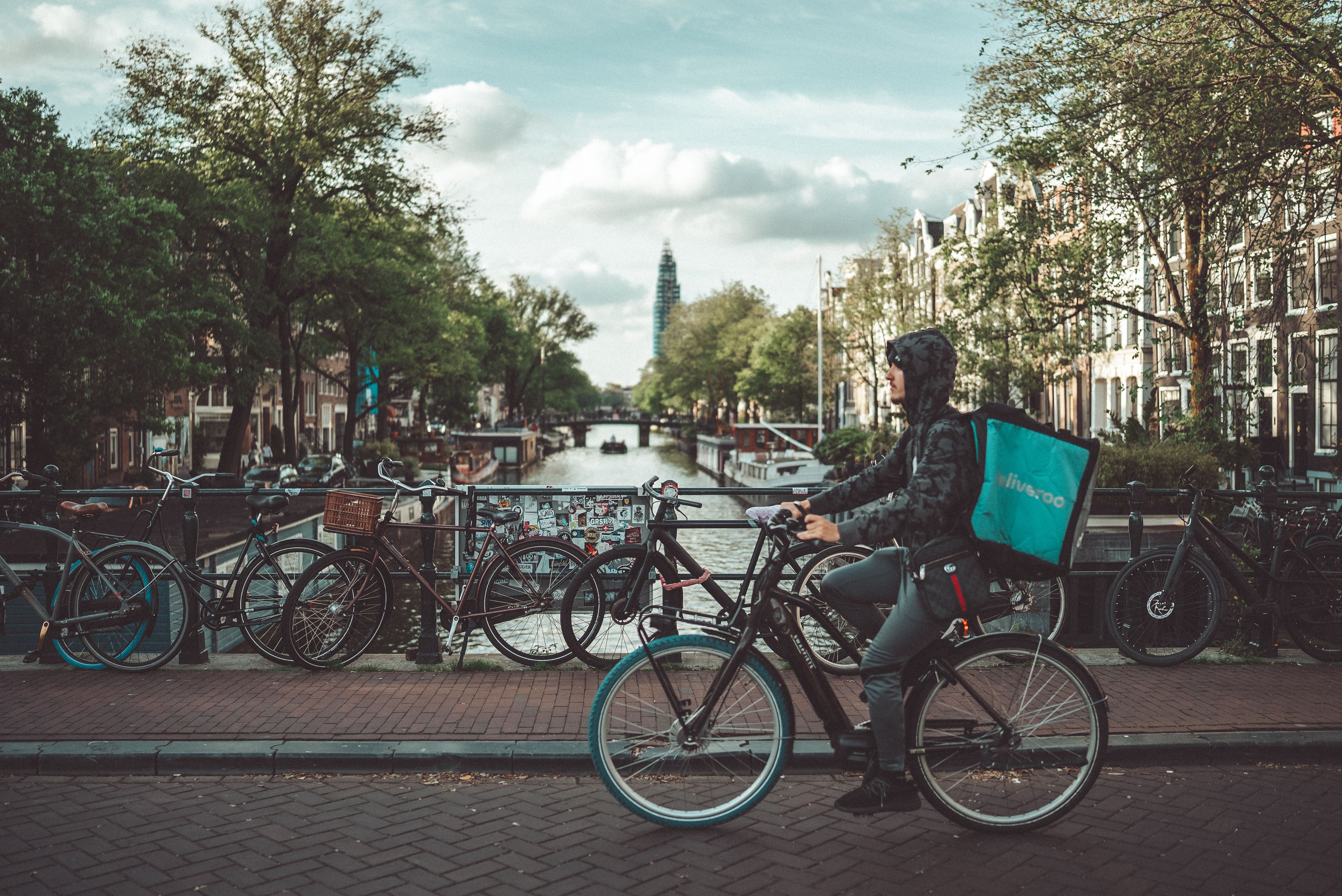 Cyclist Delivering Food in Amsterdam's Scenic Canal · Free Stock Photo