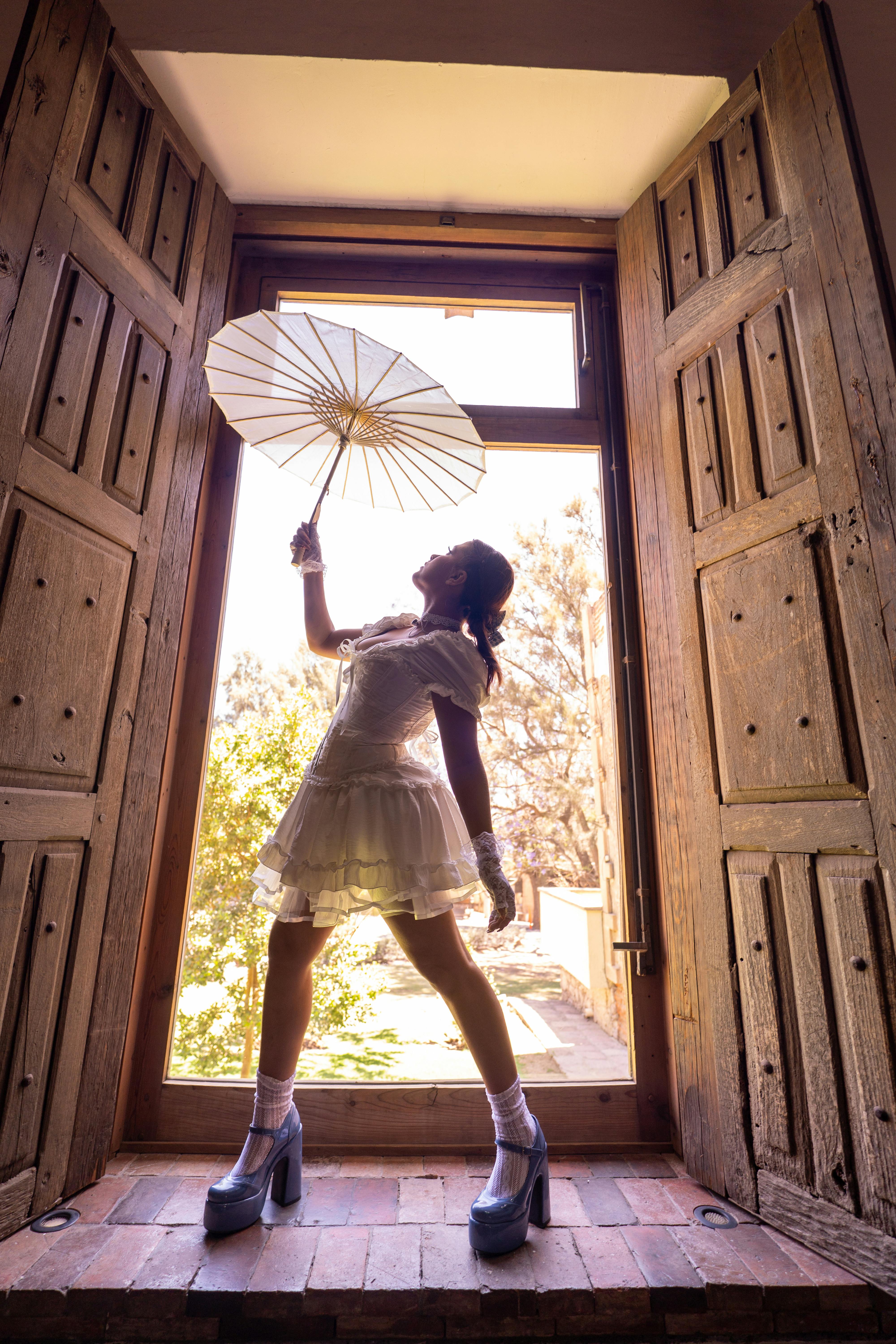Elegant Woman with Parasol in Leon Window · Free Stock Photo