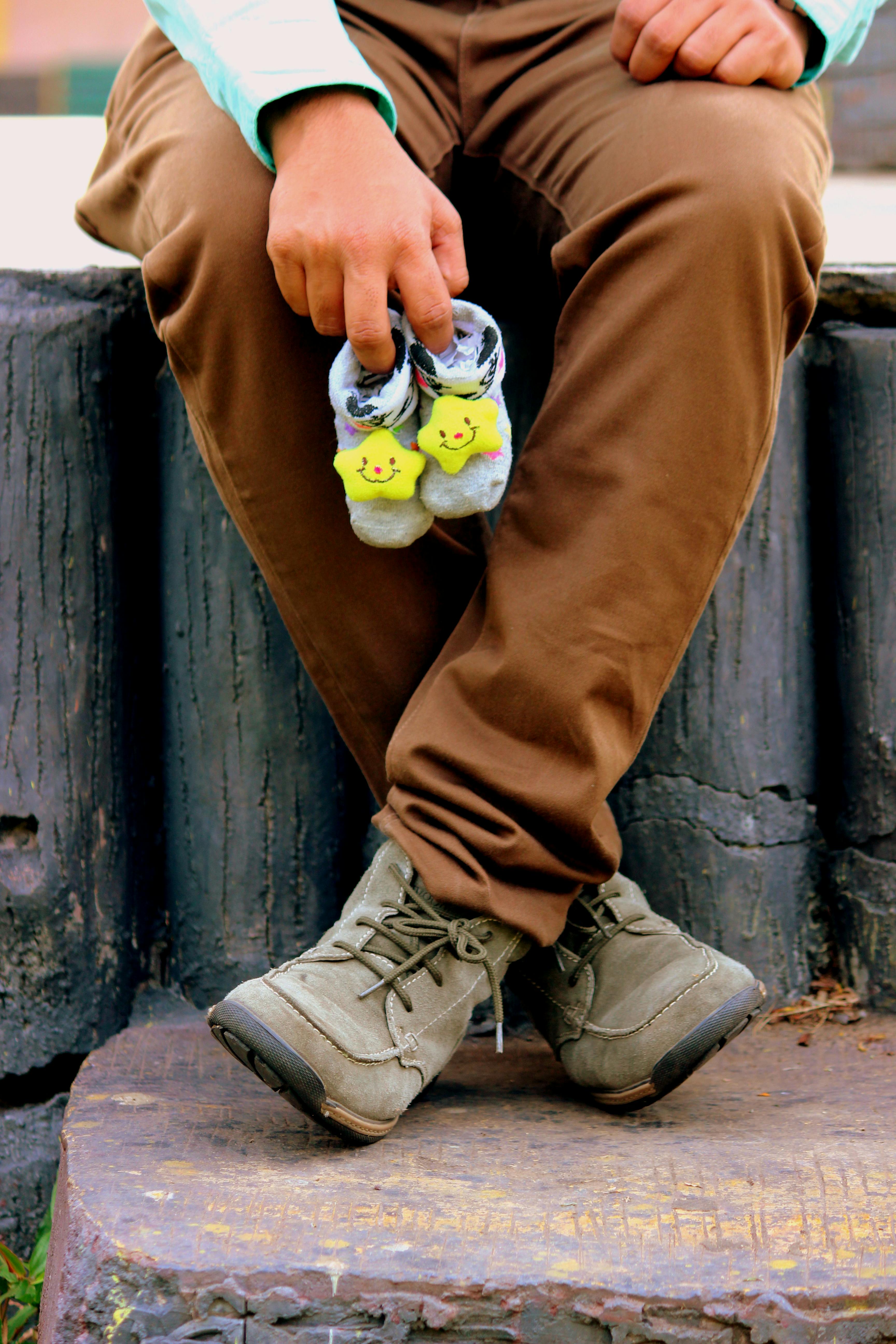 Expectant Father Holding Baby Shoes with Smiley Faces · Free Stock Photo