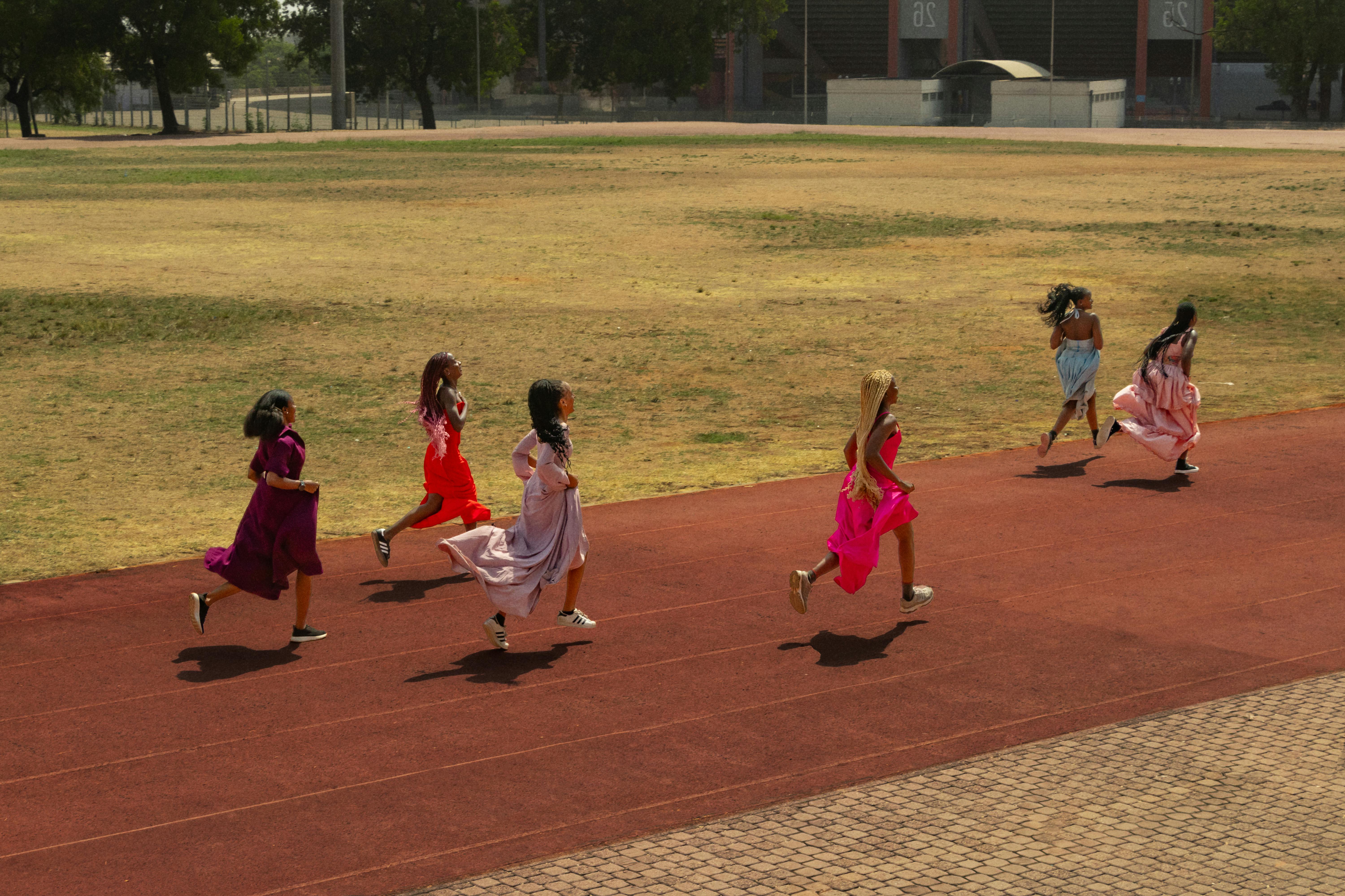 Girls Running in Colorful Dresses on Track · Free Stock Photo