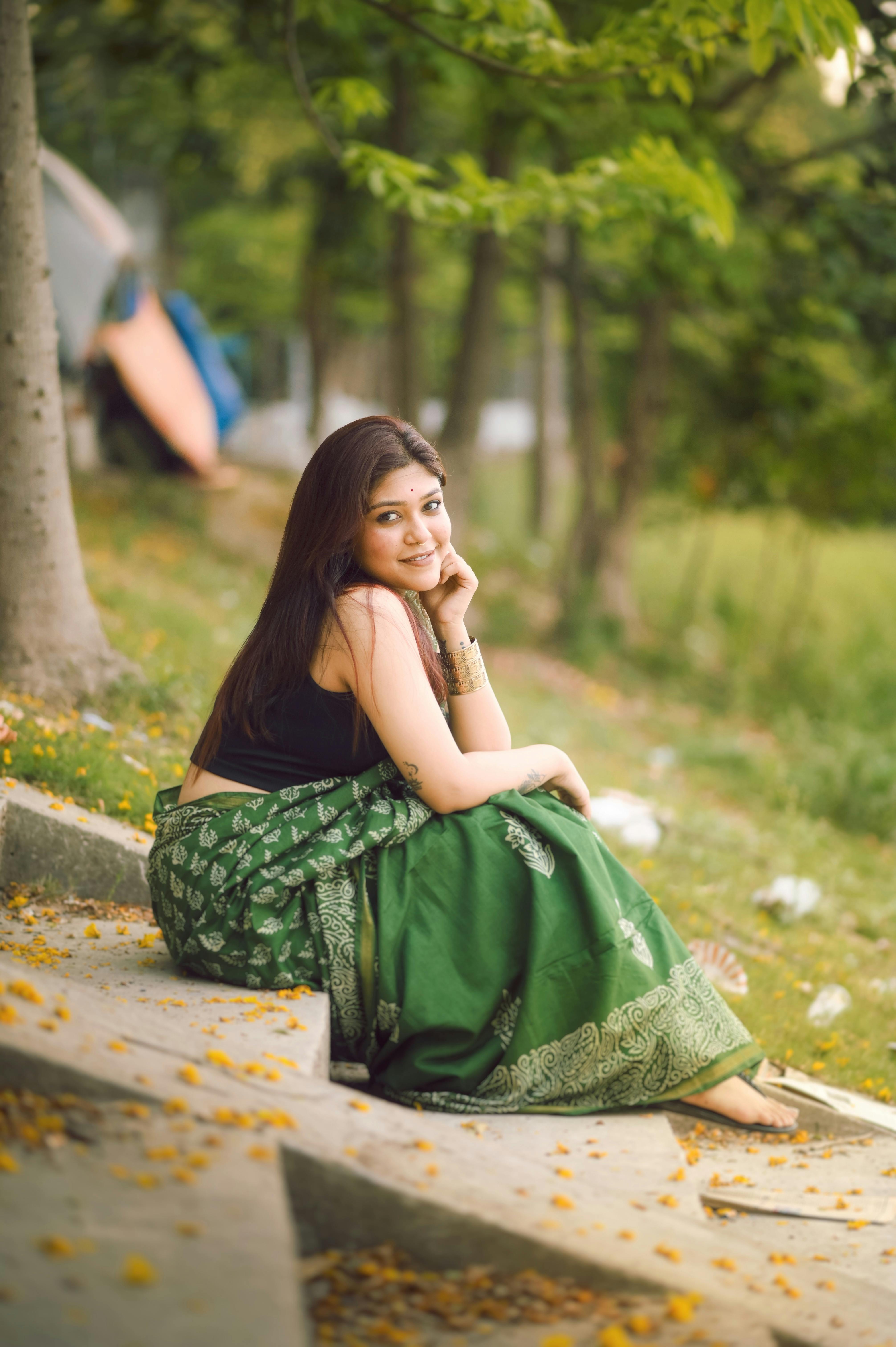 Young Woman in Green Saree Sitting Outdoors · Free Stock Photo