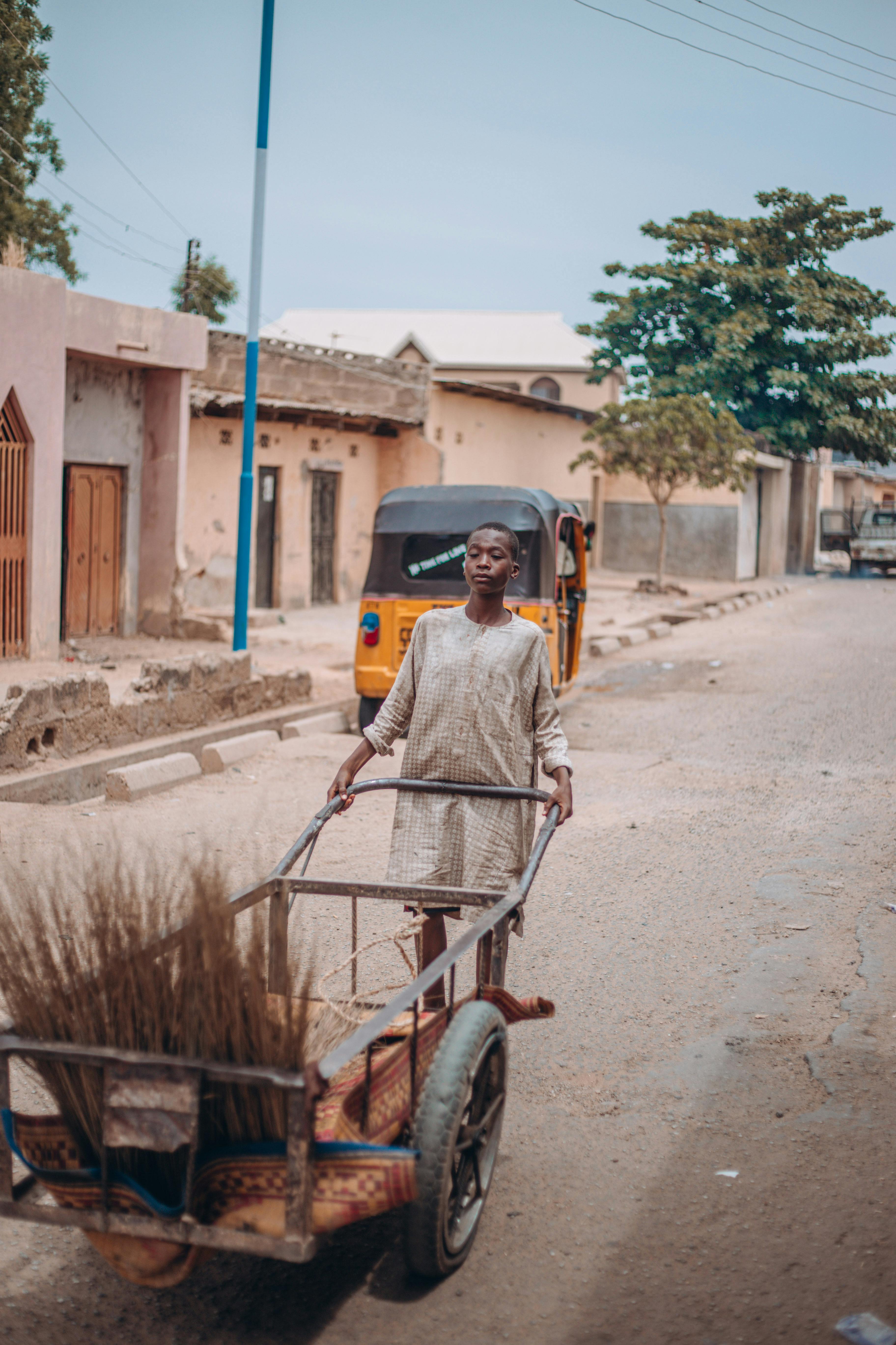 Young Man Pulling Cart on Rustic Street · Free Stock Photo