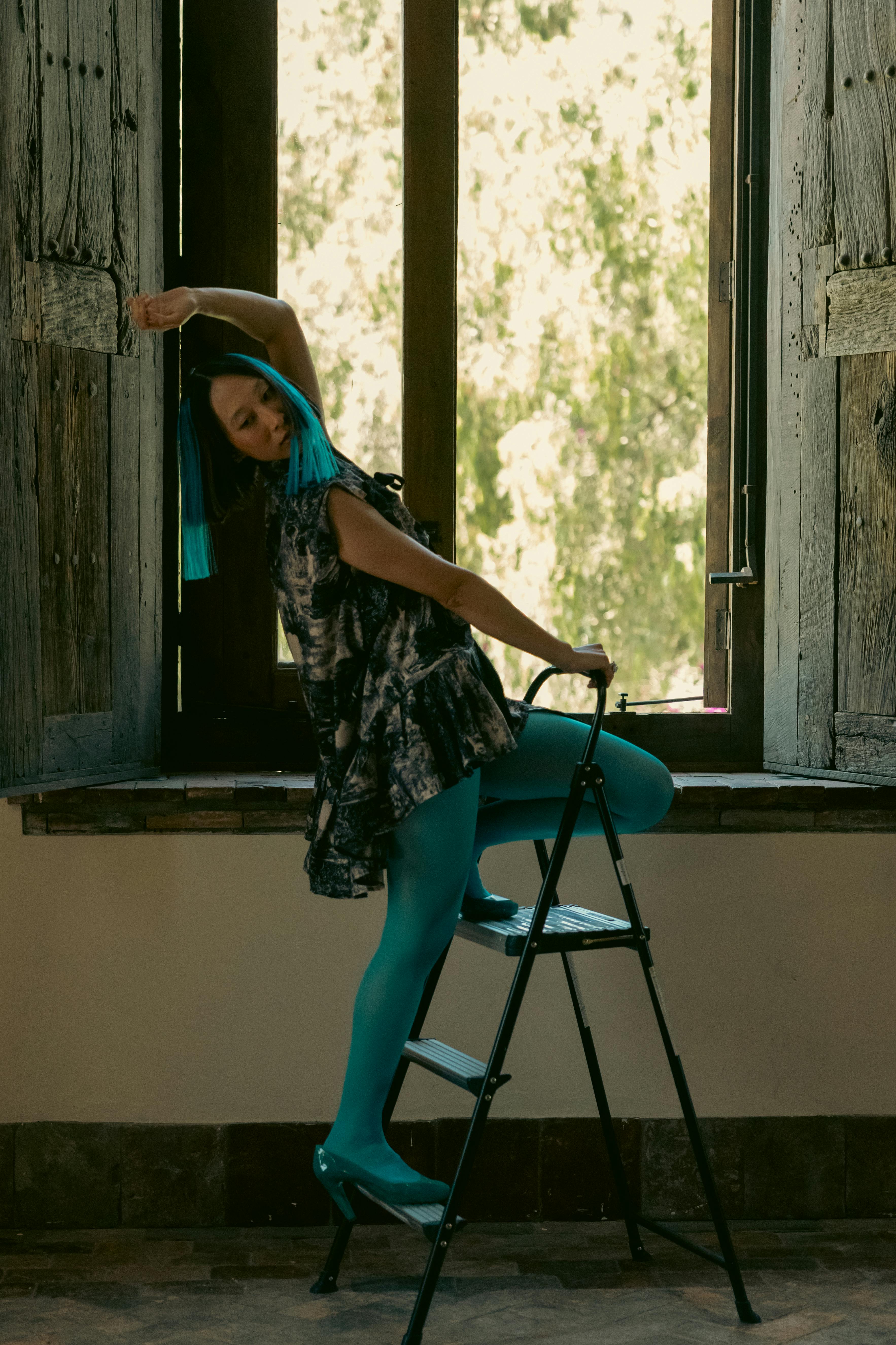 Artistic Pose of Woman on Ladder by Window · Free Stock Photo