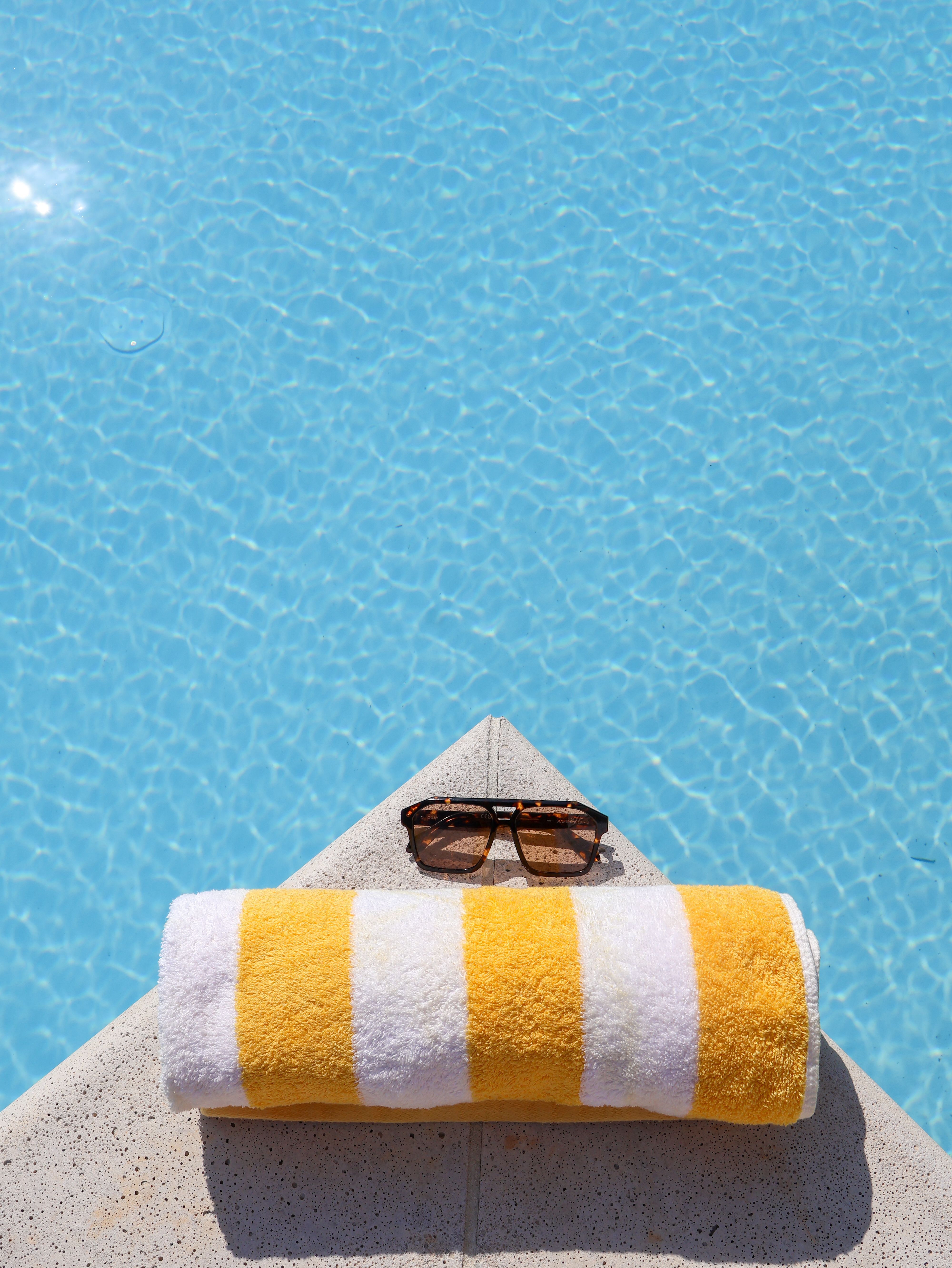 Relaxing Poolside Vibes with Sunglasses and Towel · Free Stock Photo