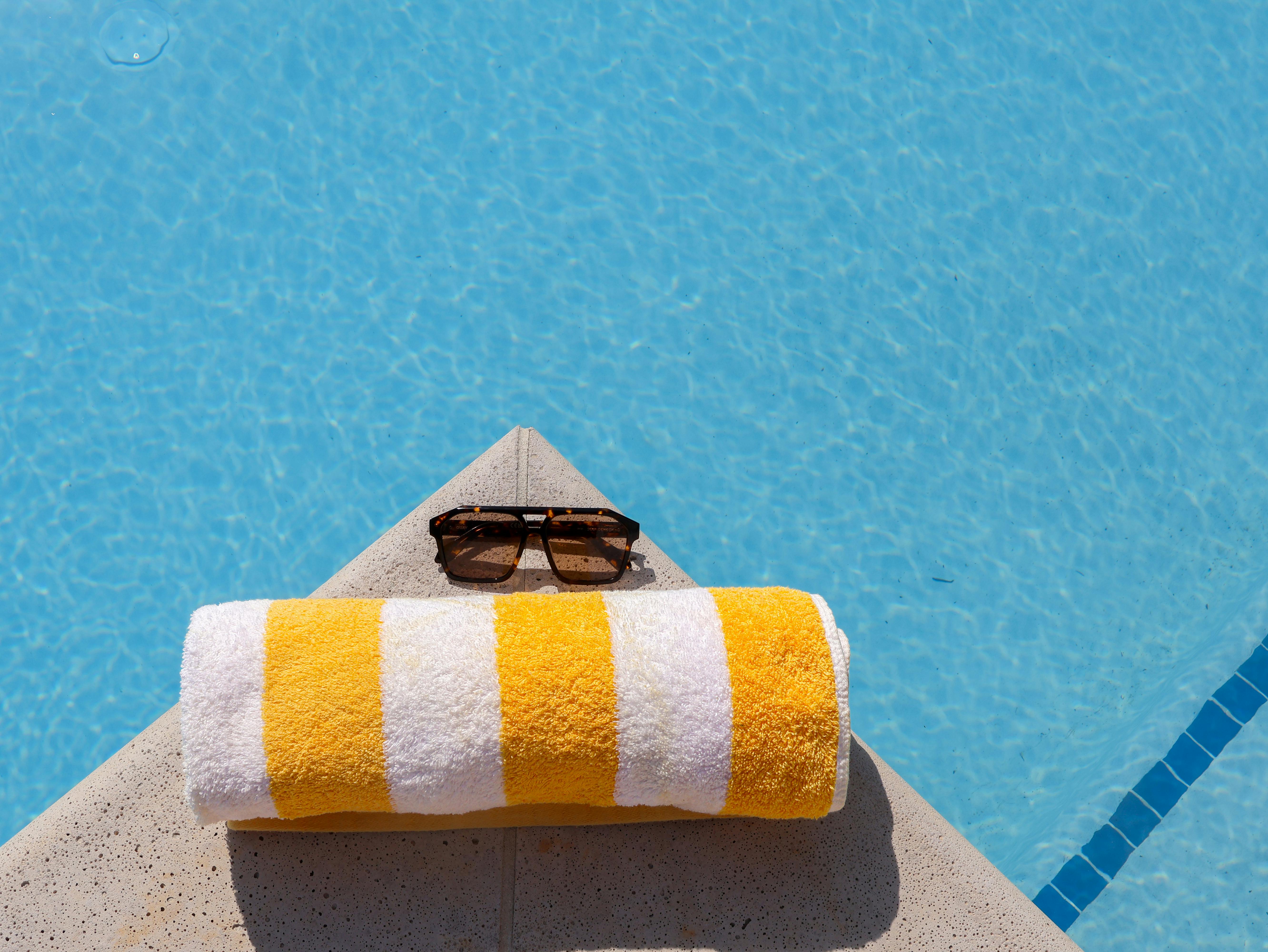 Sunny Poolside with Sunglasses and Towel · Free Stock Photo