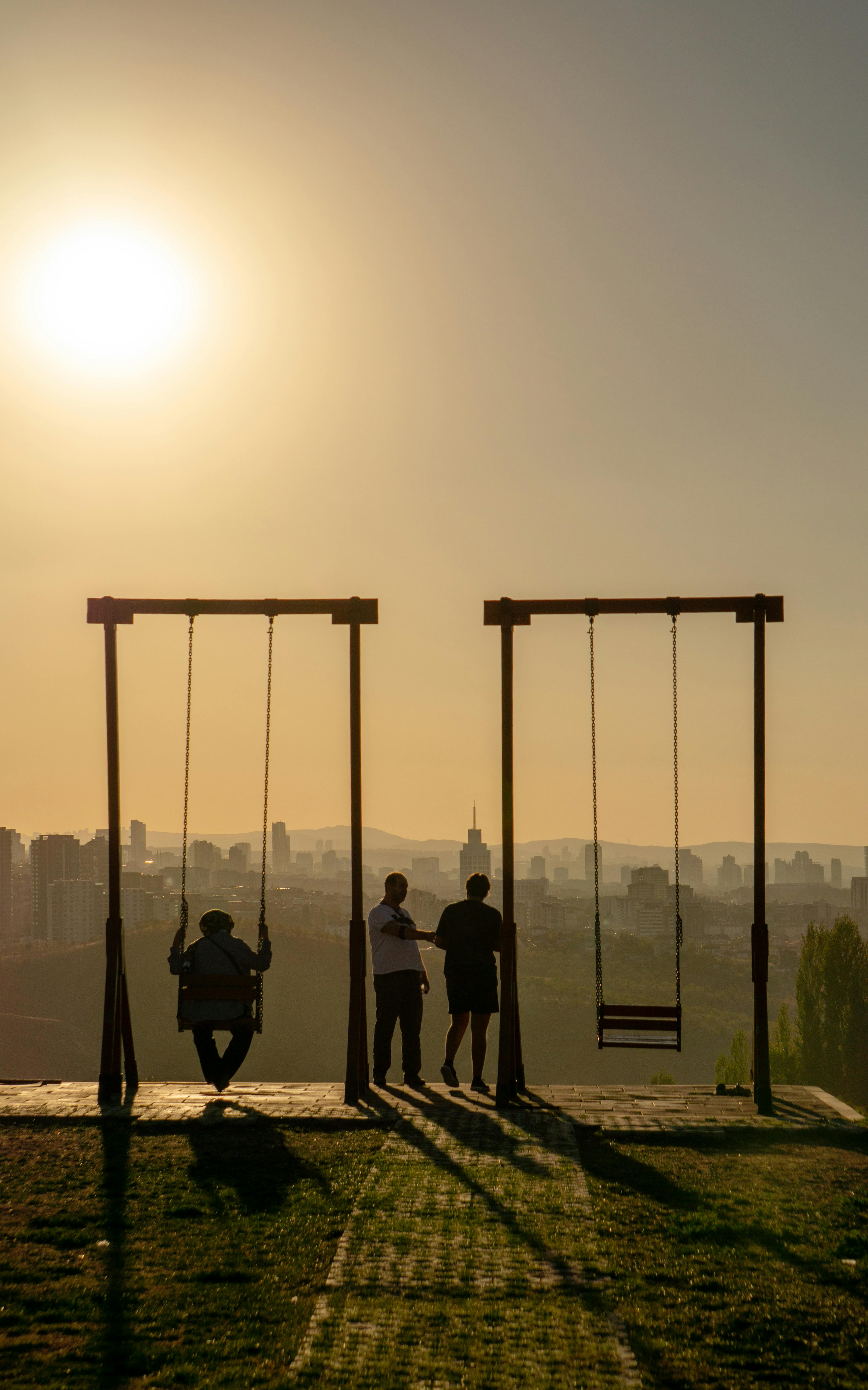 Silhouetted Group Watching Sunset on Swings · Free Stock Photo