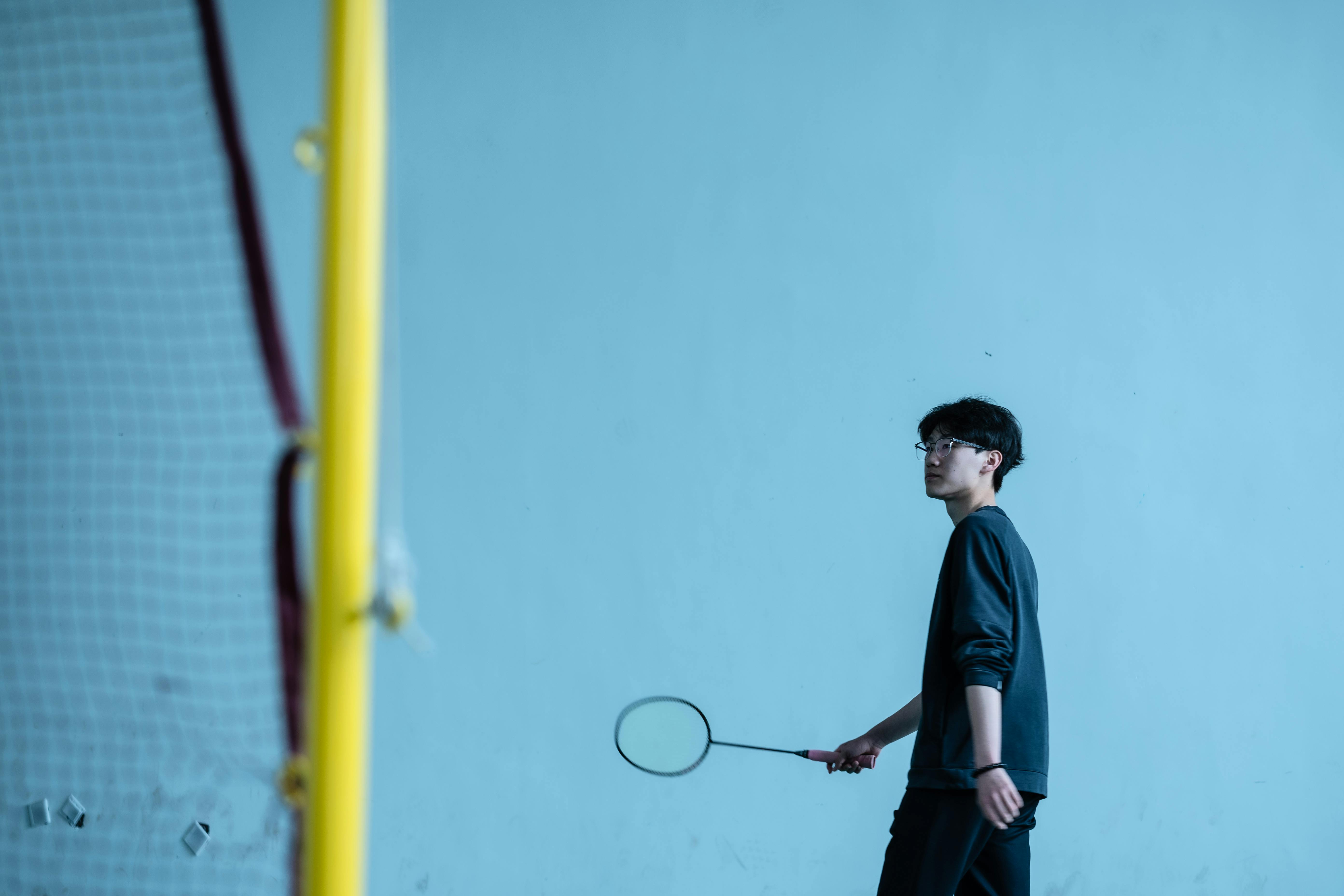 Young Man Playing Badminton Indoors · Free Stock Photo