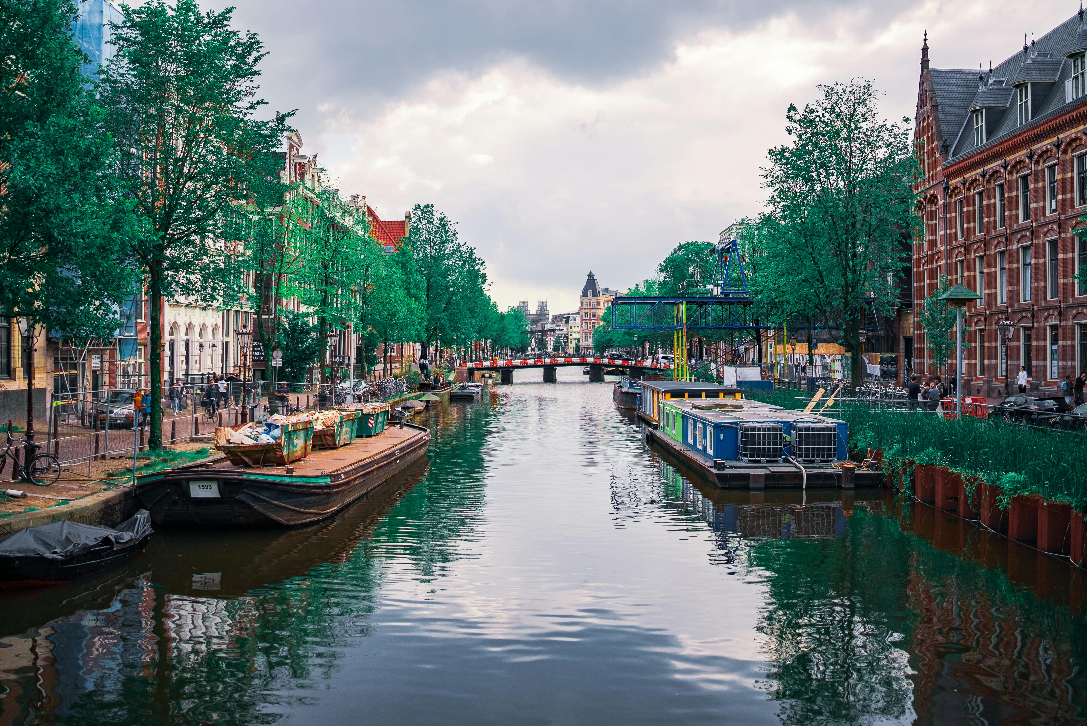 Serene Amsterdam Canal Scene with Vibrant Buildings · Free Stock Photo