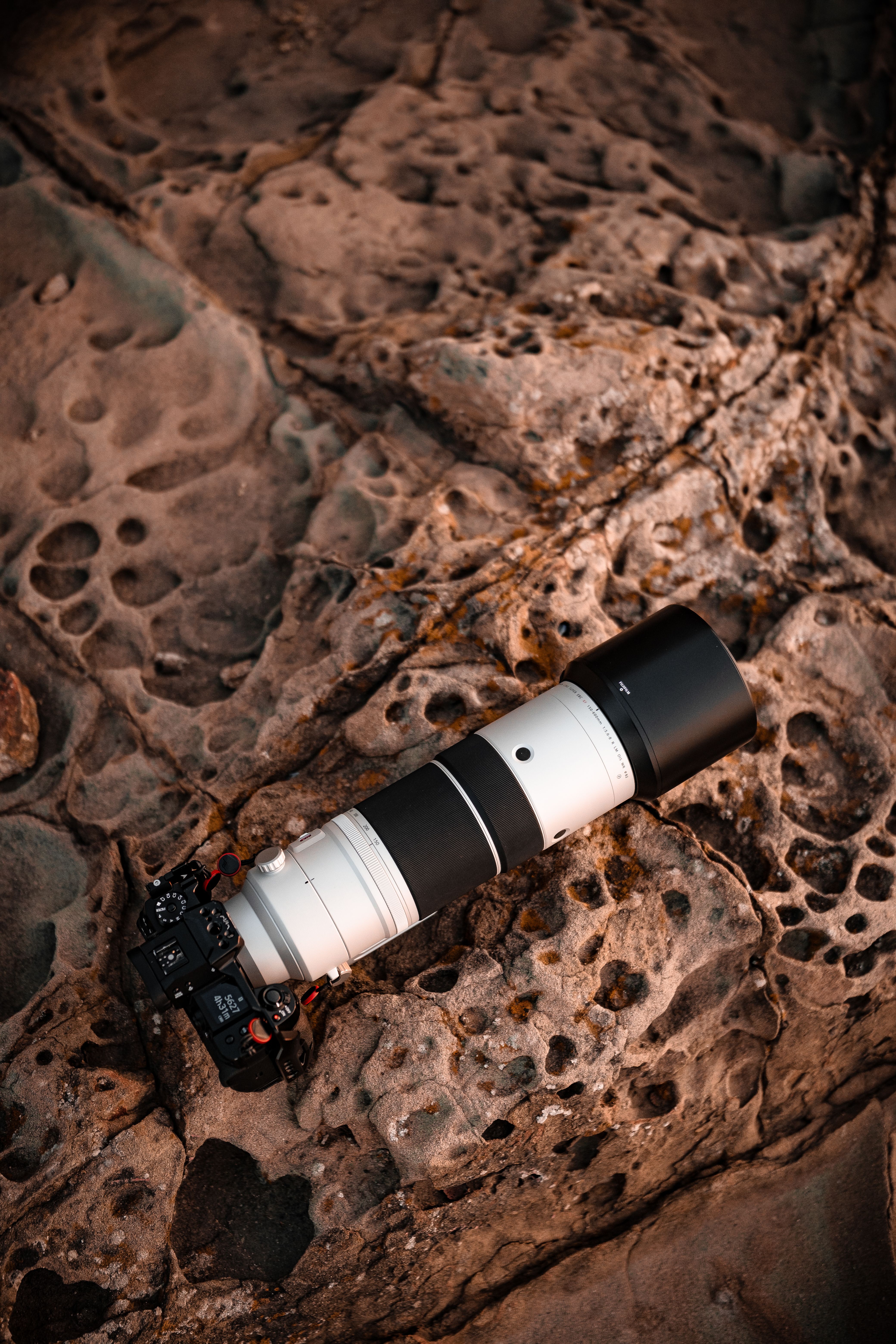 Long Telephoto Camera Lens on Rocky Surface · Free Stock Photo