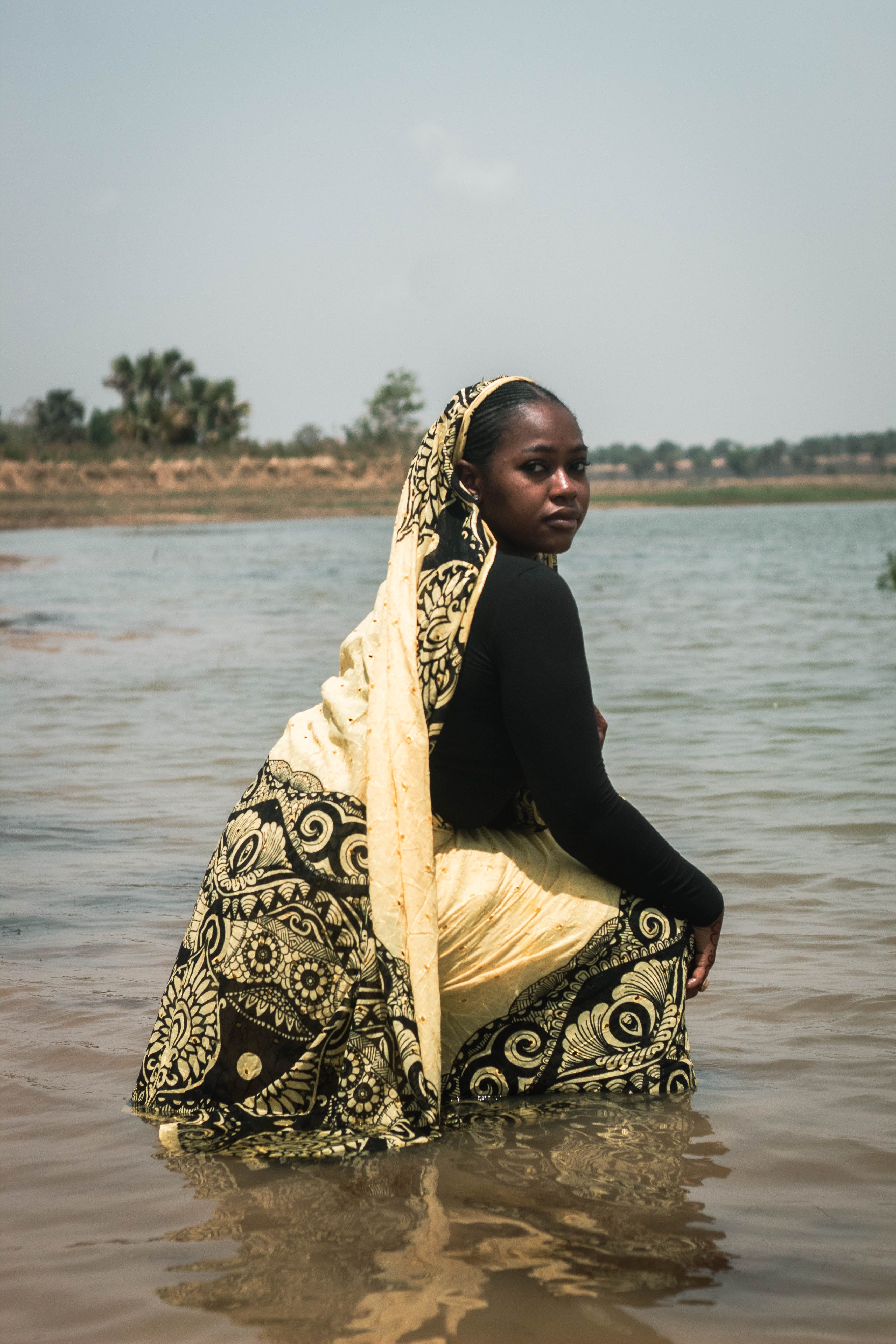 Woman in Traditional Attire near Riverside · Free Stock Photo