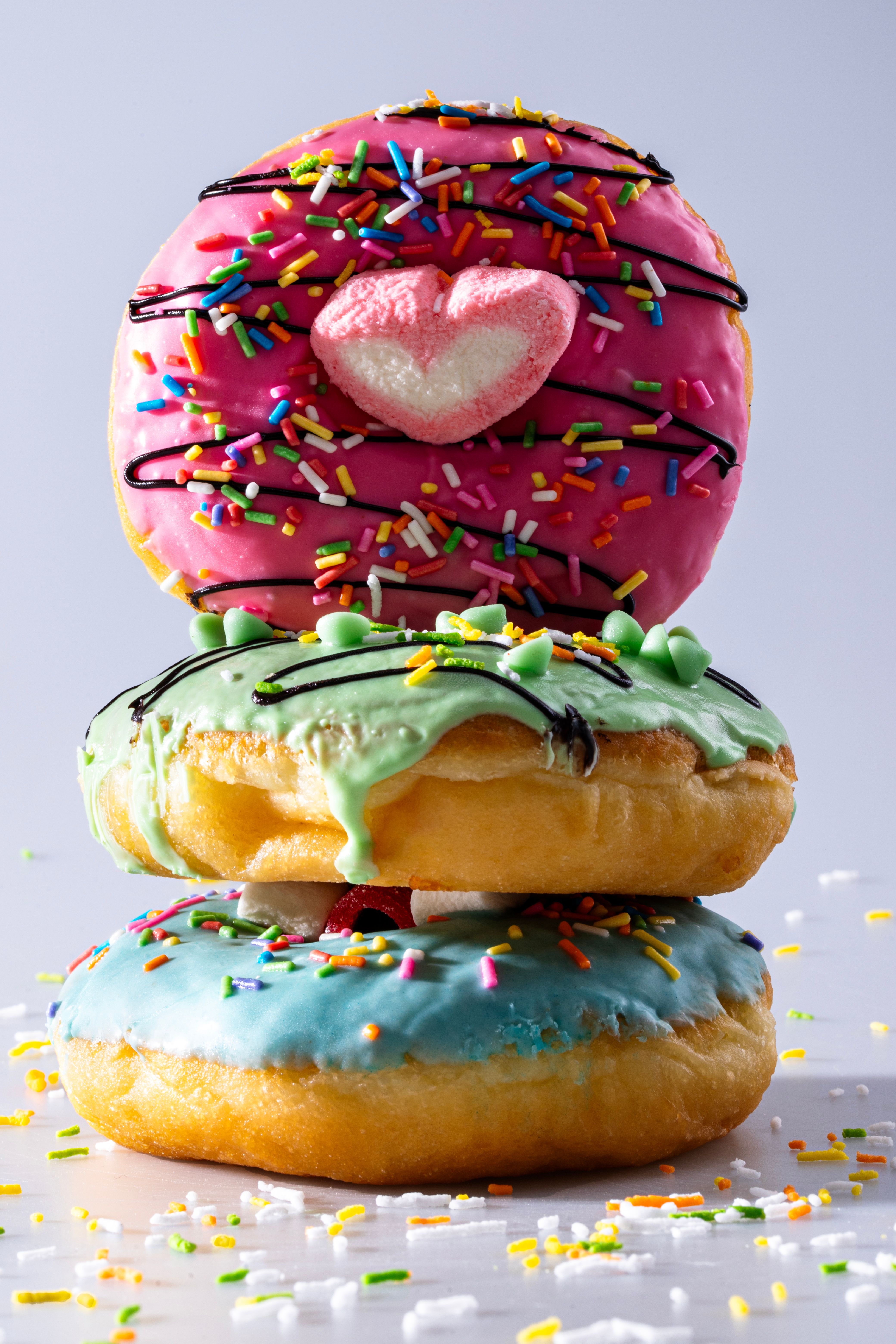 Colorful Triple Donut Stack with Sprinkles · Free Stock Photo